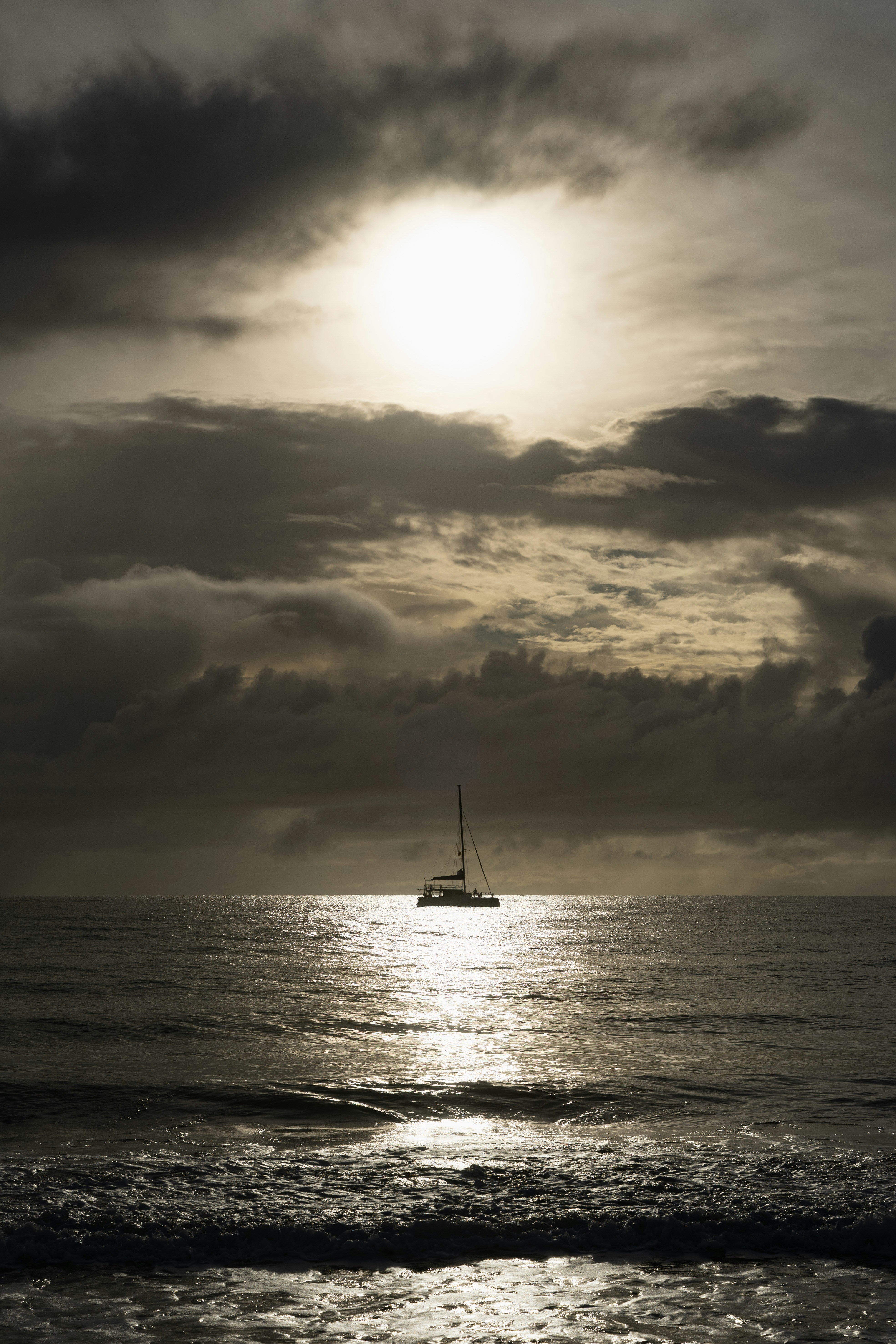 Silenced Horizon: A Sailboat Beneath a Grand Sky