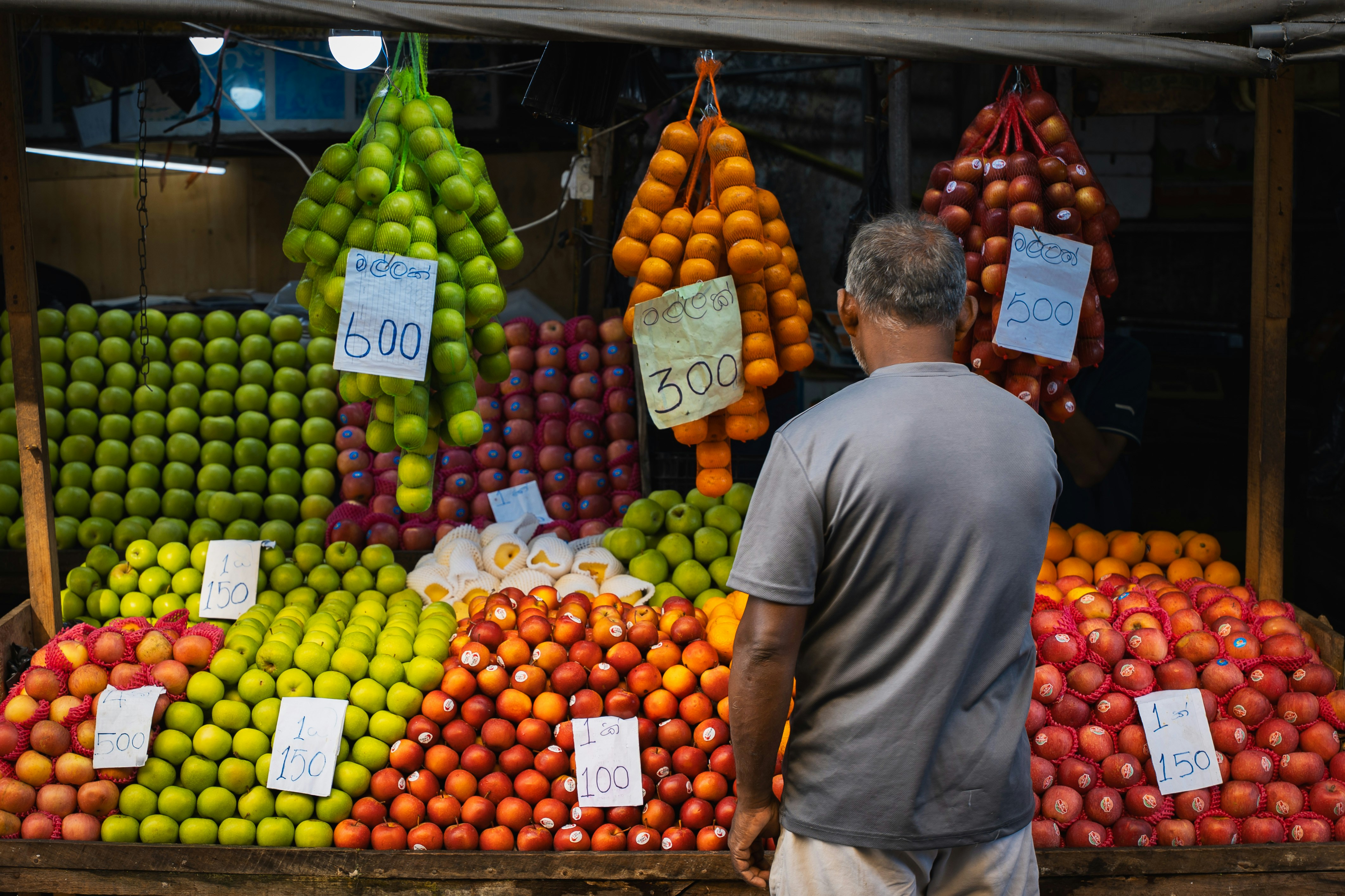 Market Vase of Color: A Vendor and a Sea of Citrus and Tomatoes