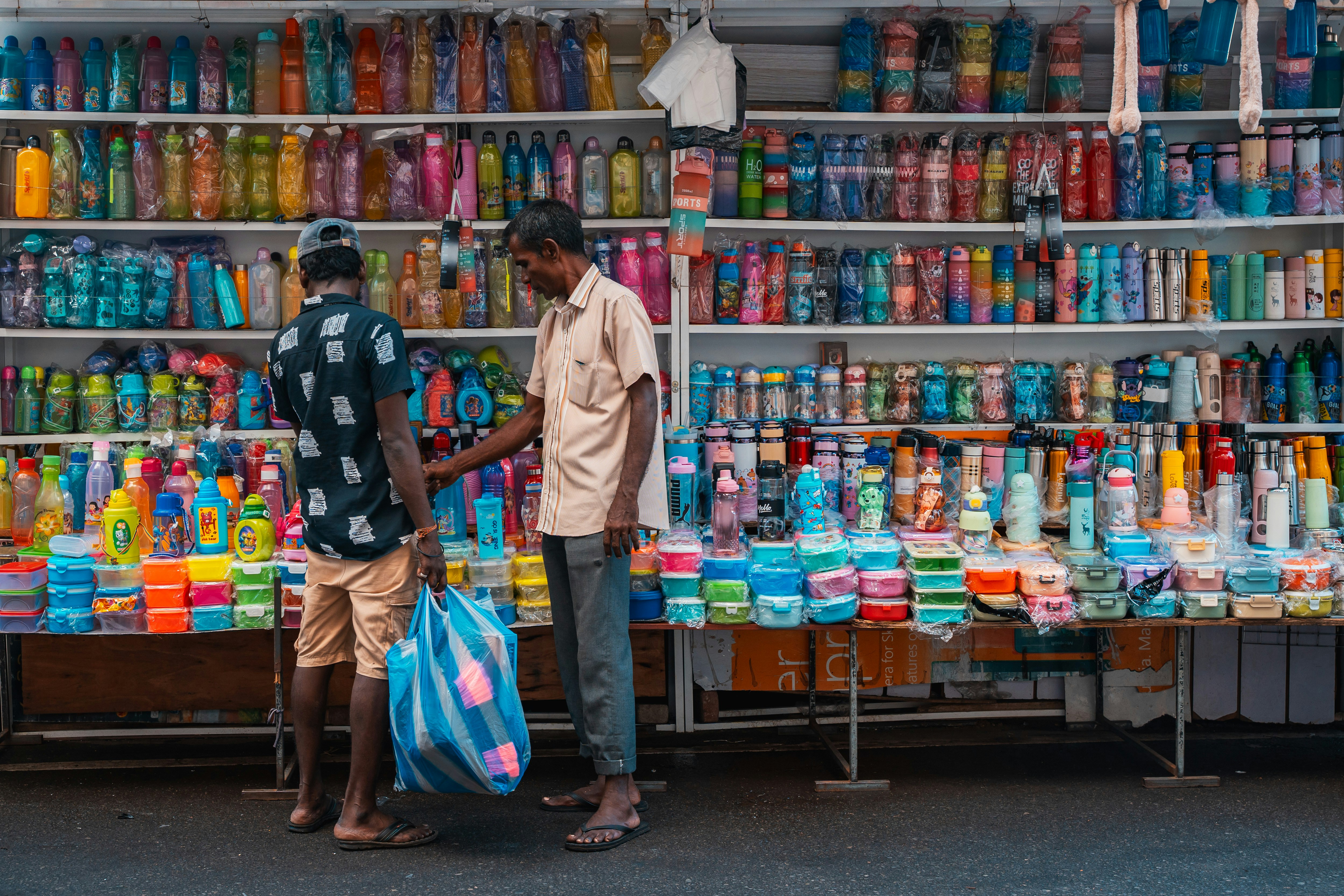Colorful Trade: Two Men Bargain in a Wall-of-Prices