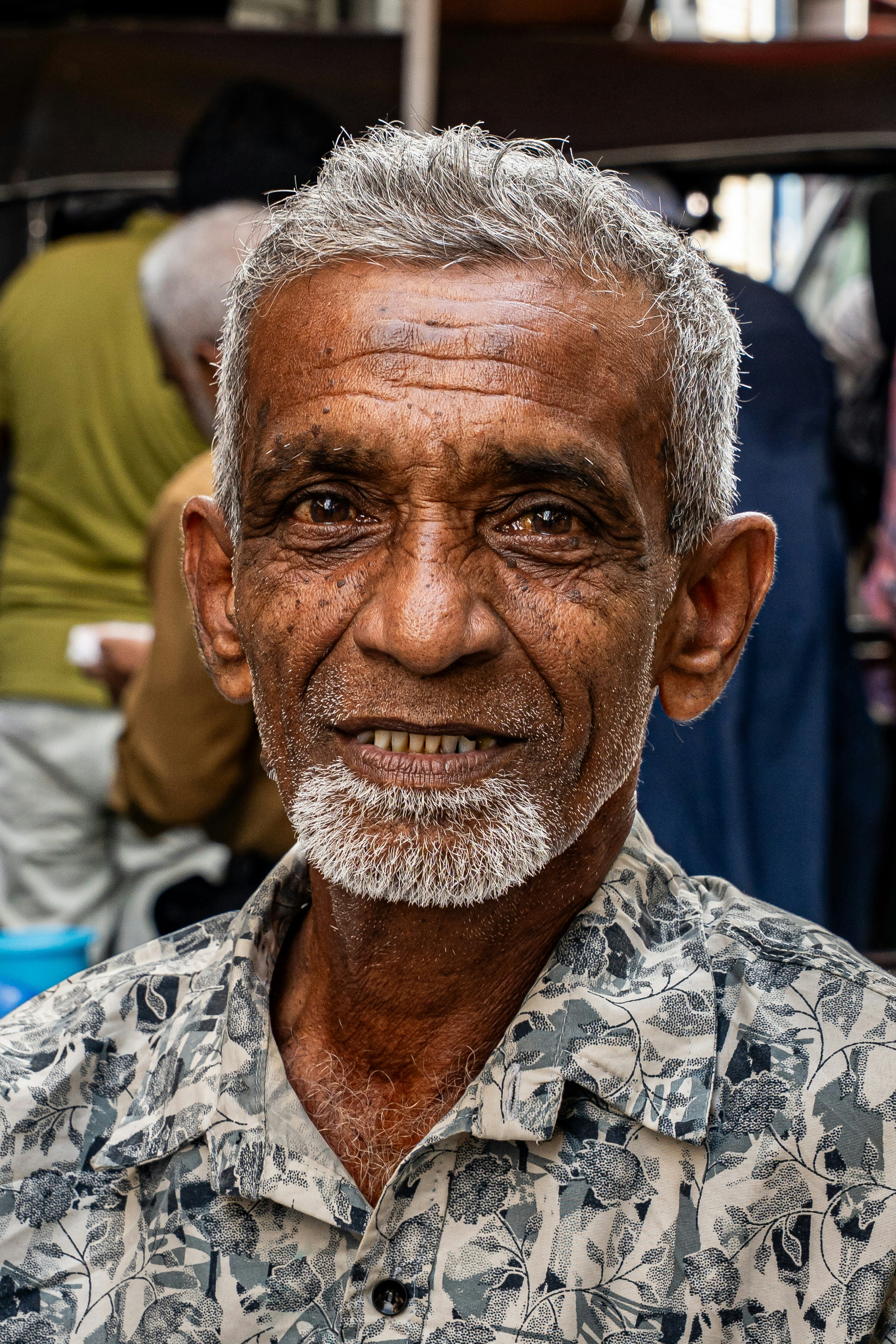 Warmth in the Market: A Weathered Smile Beneath Sunlit Grey