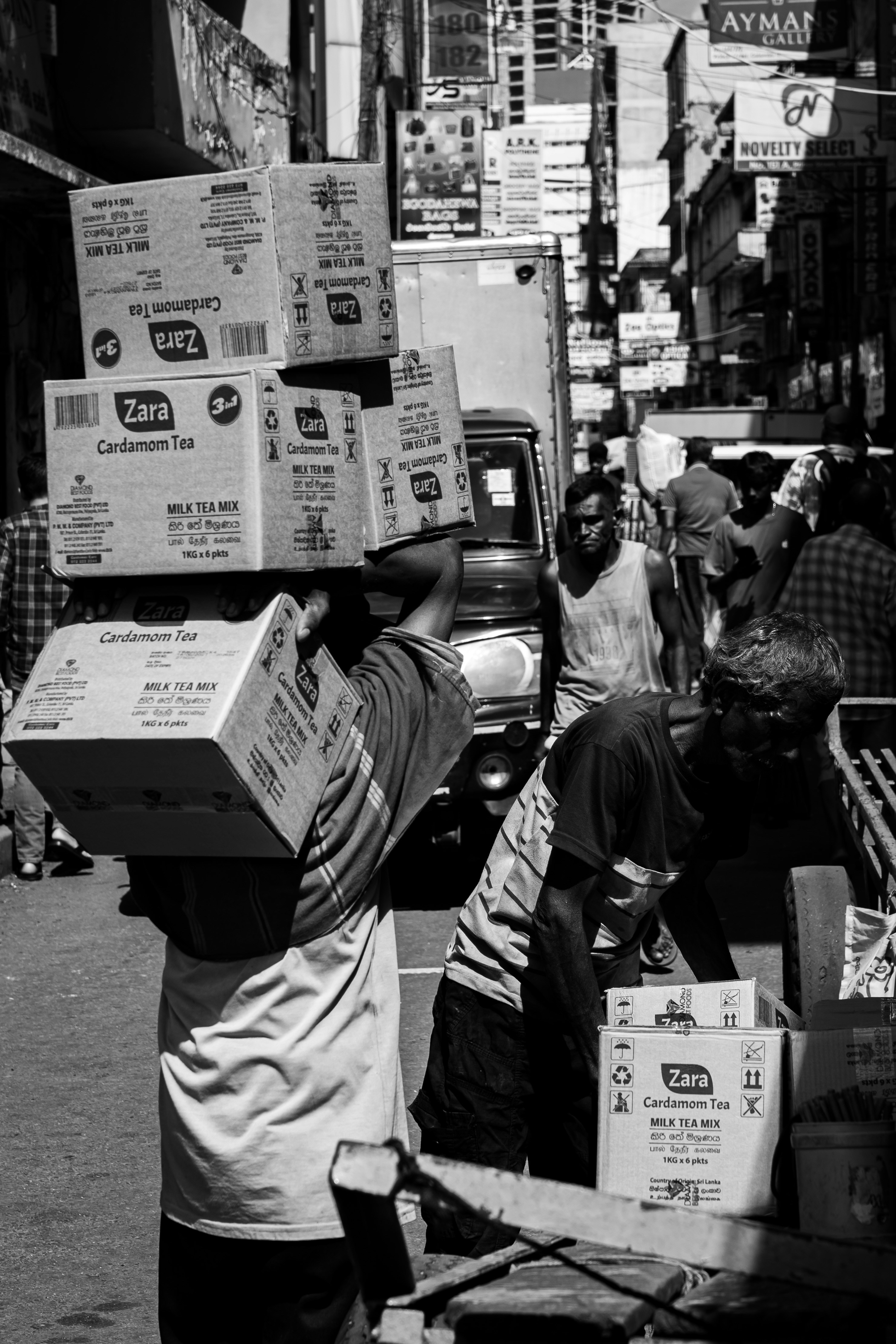 Cartons on a crowded street: a laborer's burden through the urban tide