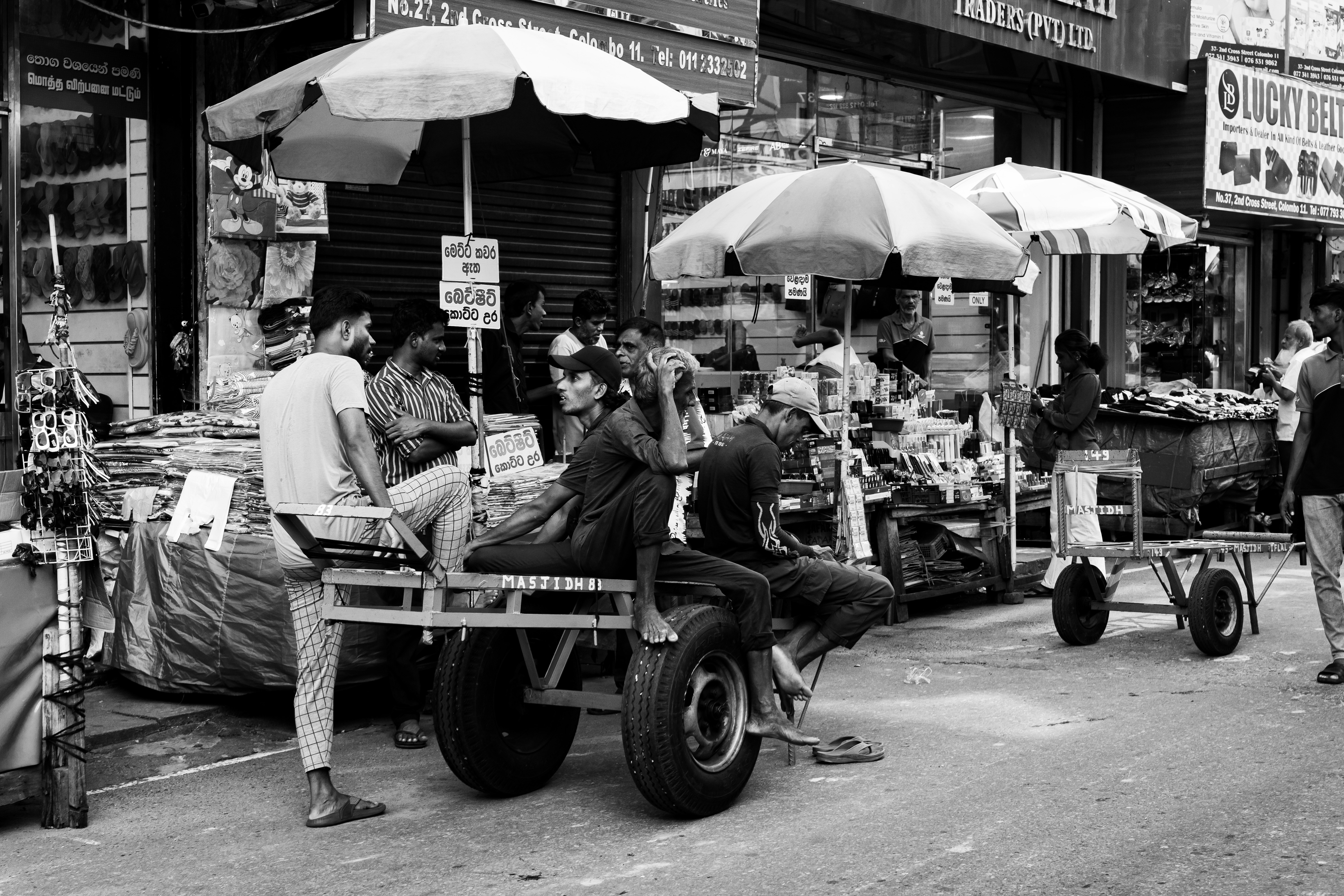 Street Cart Portrait: A Row of Vendors and Passersby Under Umbrella Canopy