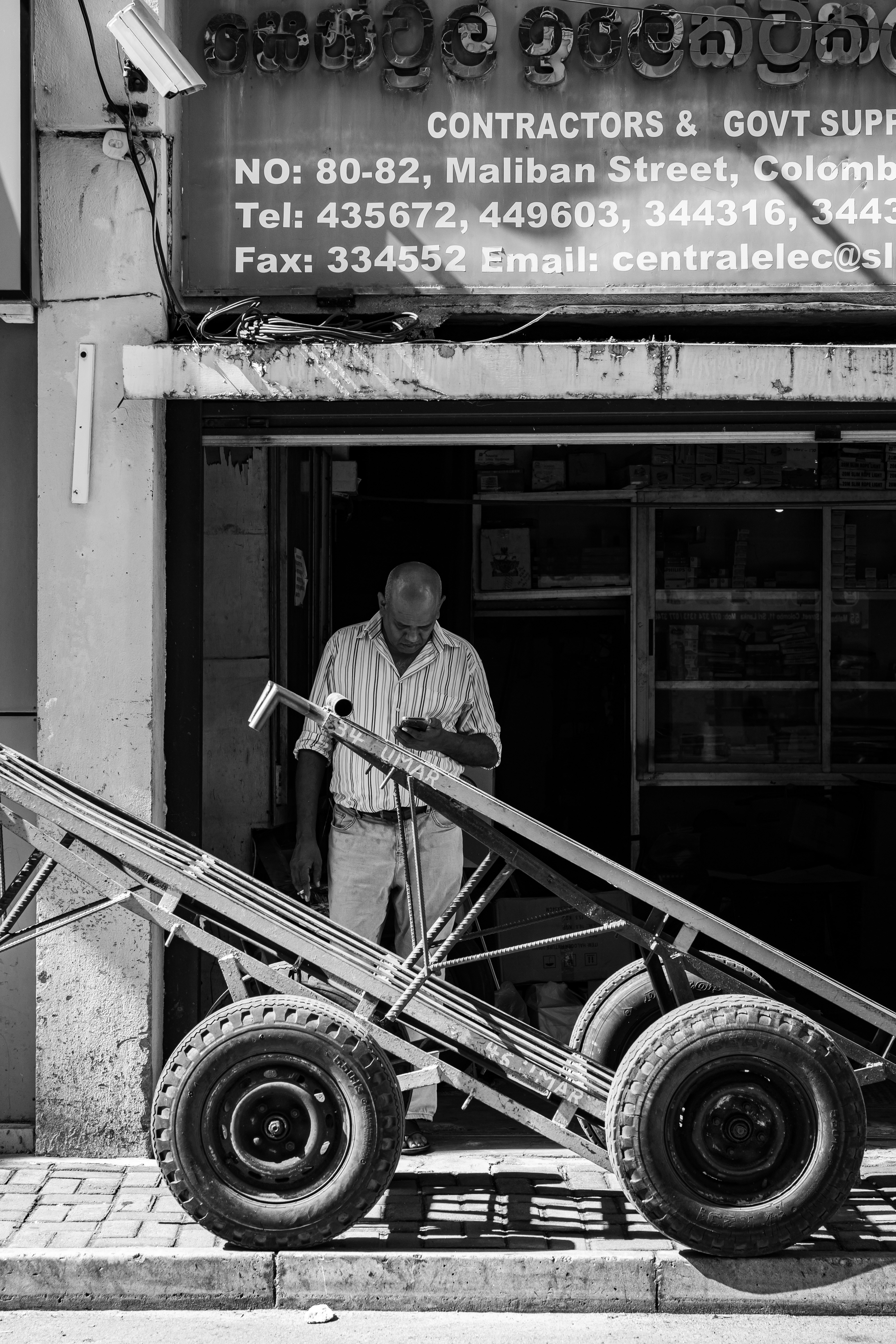 Under the Sign, a Mechanic Pauses to Check the Work