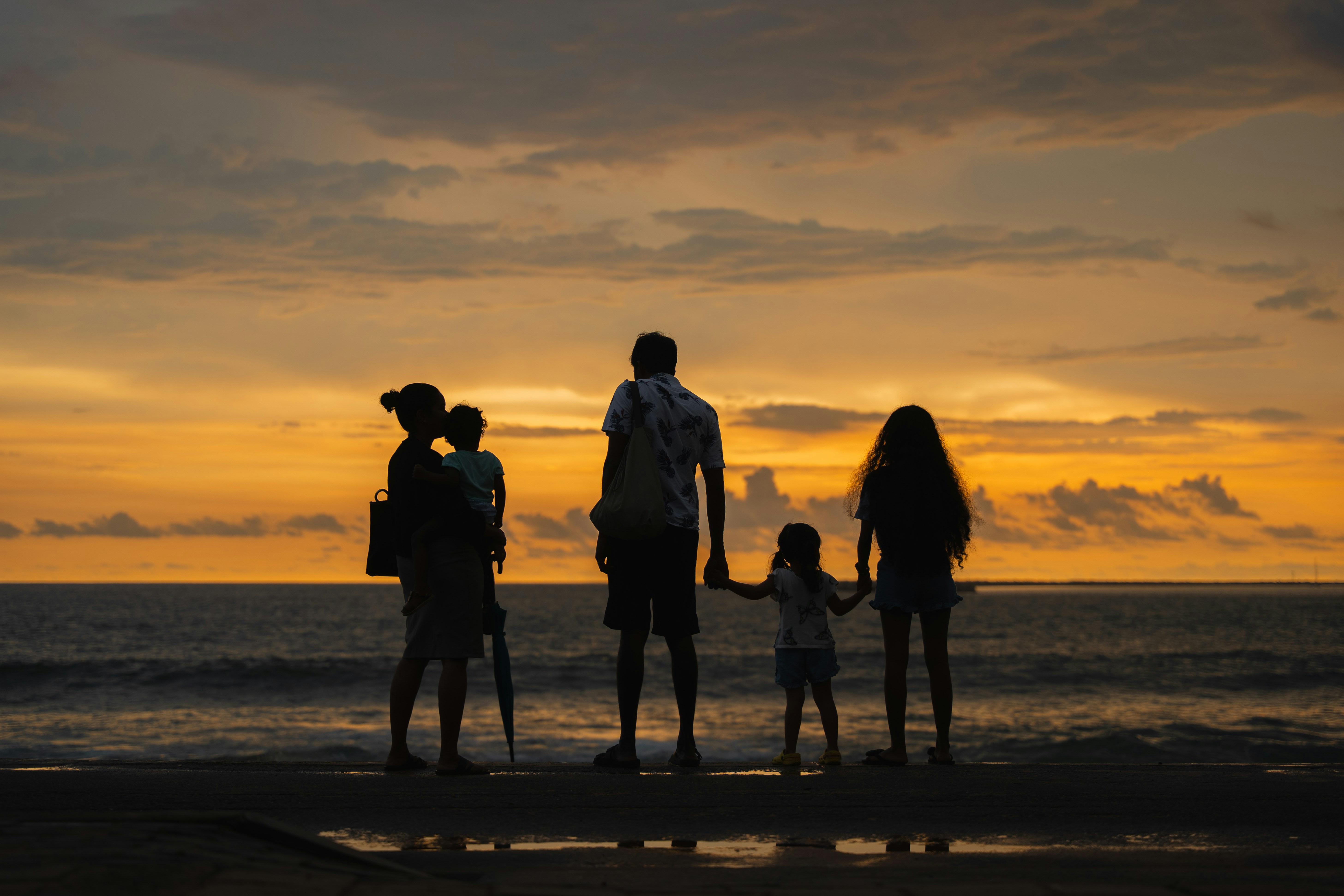 Sunset Silhouettes: A Family Standing at the Edge