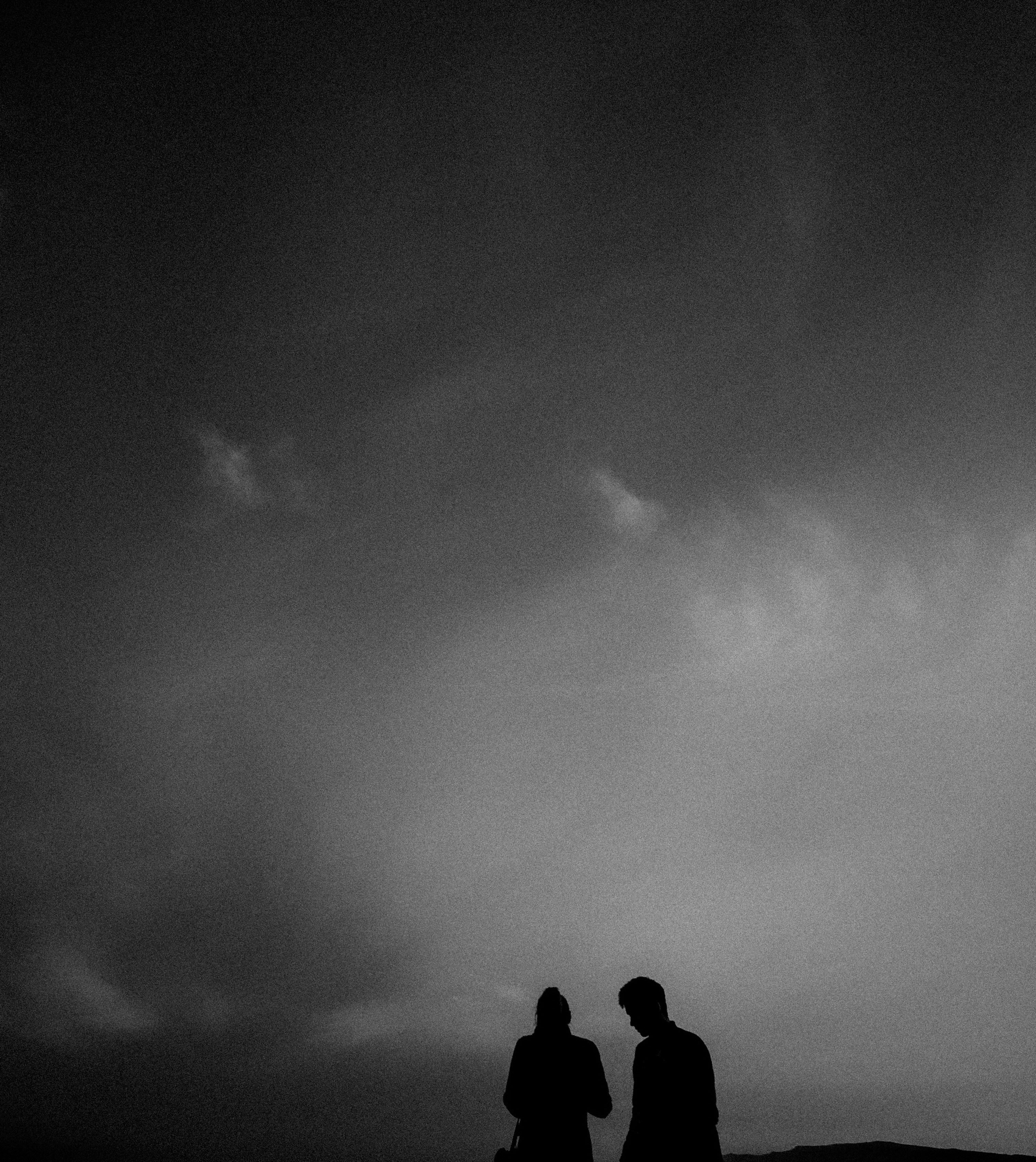 Silhouetted Couple Beneath a Vast, Cloudy Sky