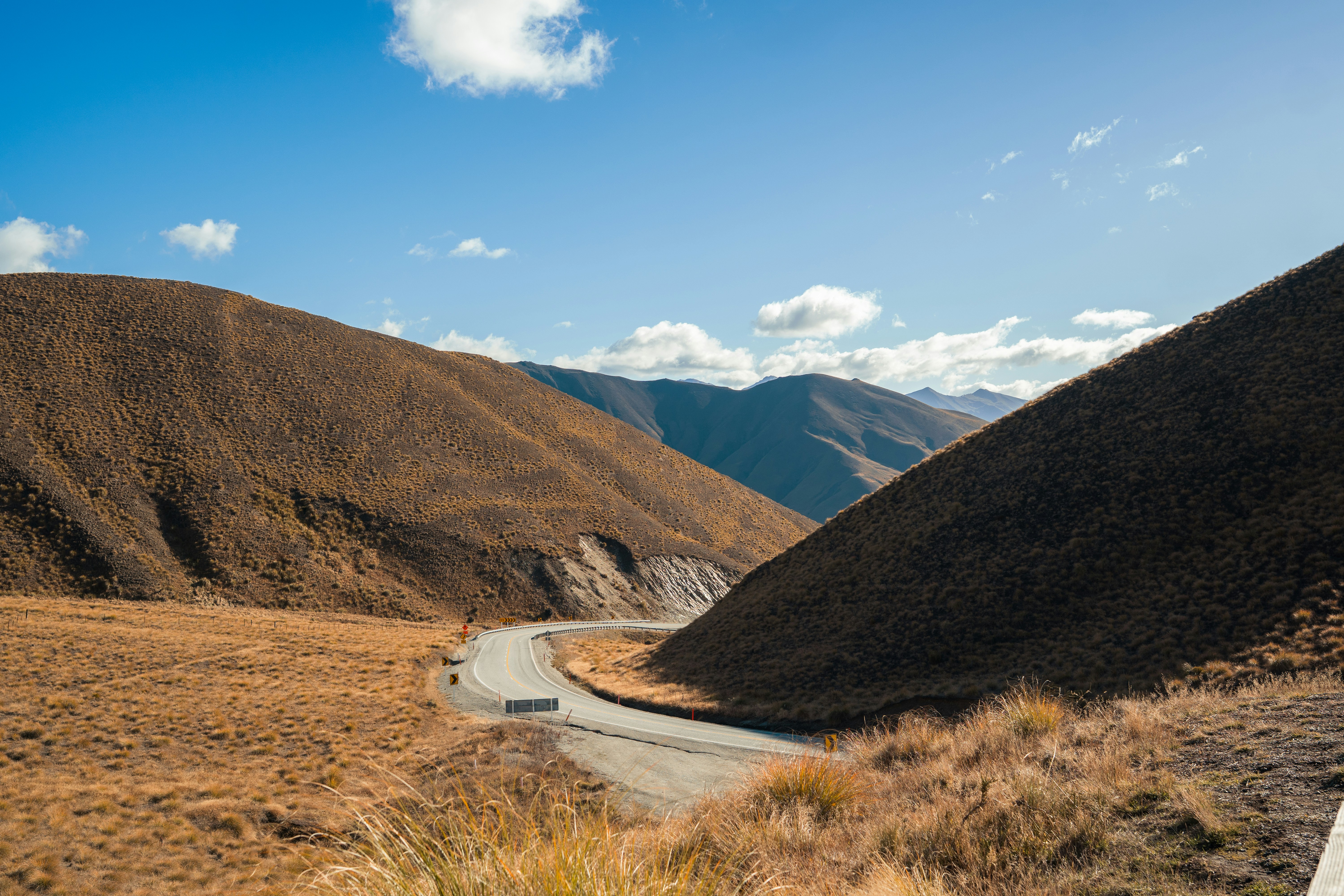 Desert Road Winding Through Golden Hills Under a Clear Sky