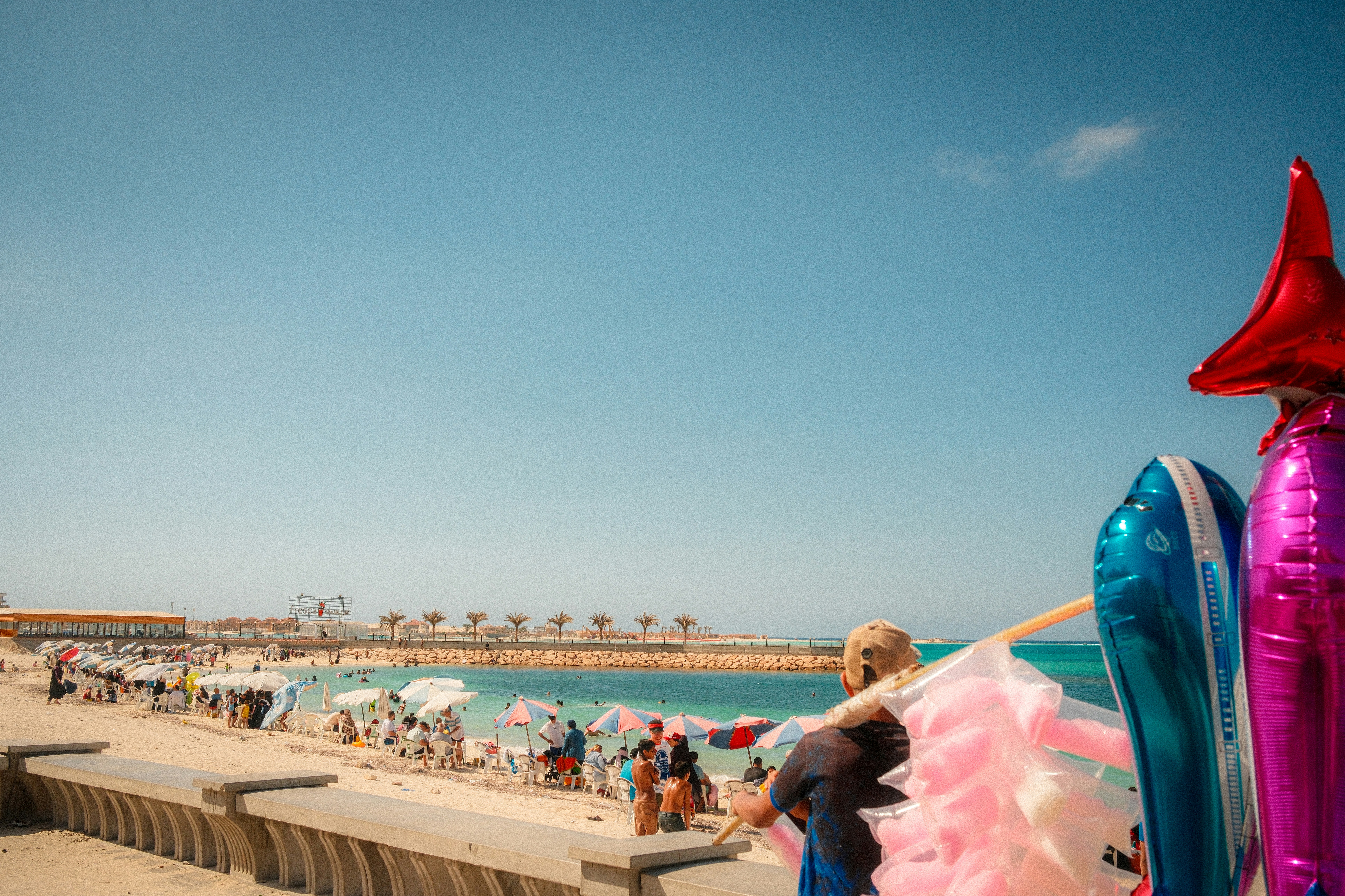 Beachside Bazaar: Floating Balloons and a Wind-Swept Crowd