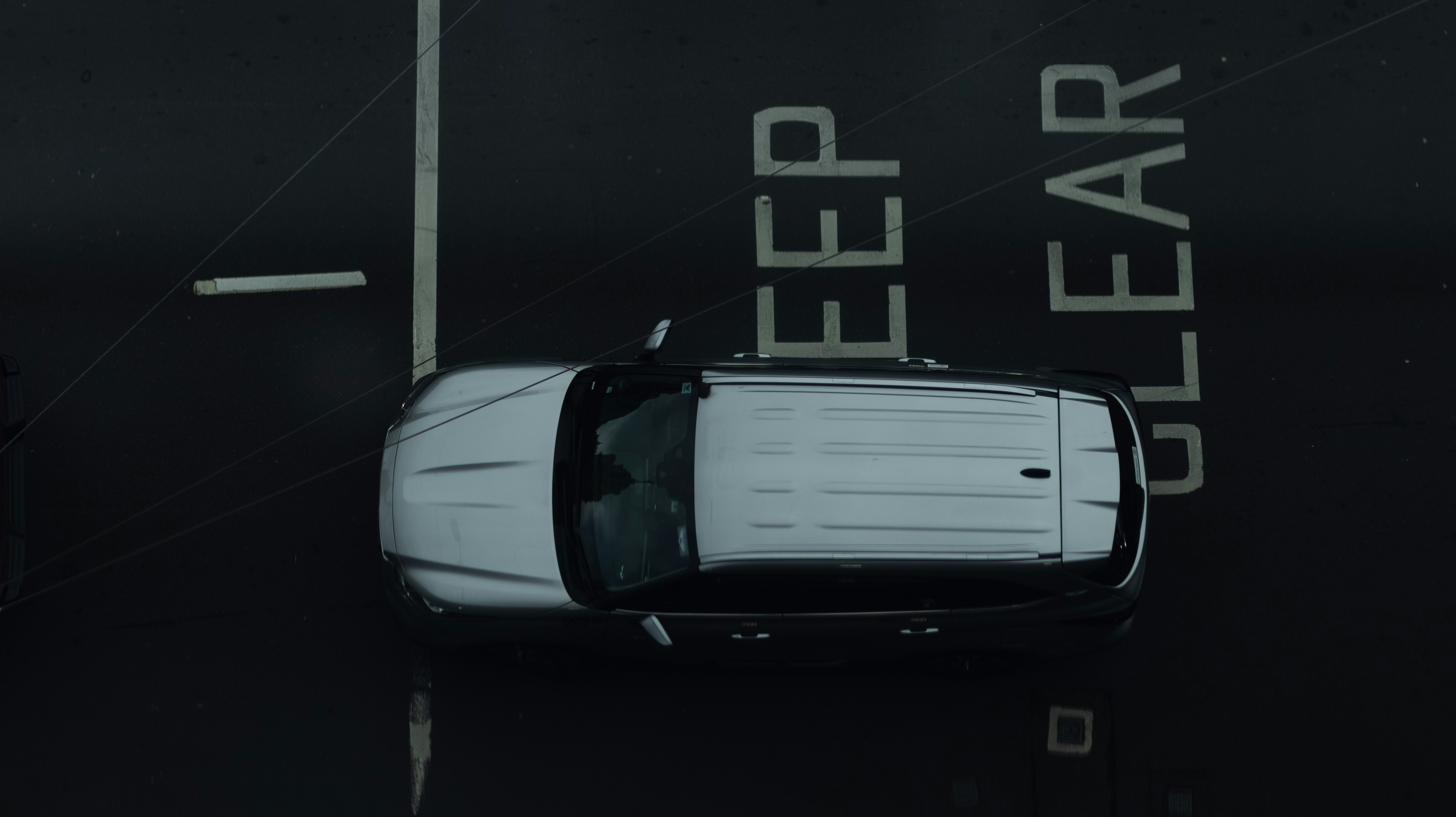 Overhead Parking: A White Vehicle Lined Up in a Quiet Lot