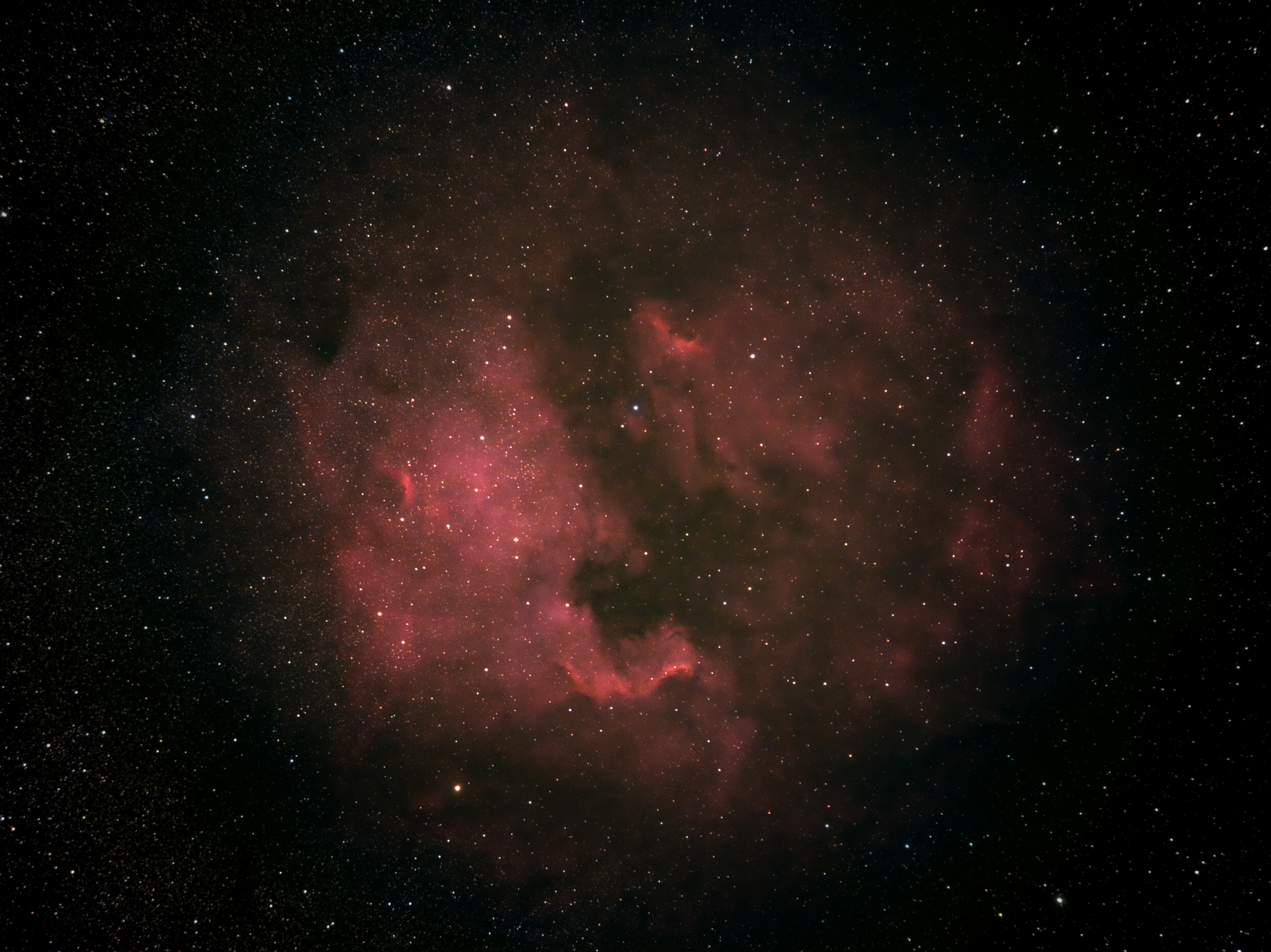A glowing red nebula in deep space with many stars.