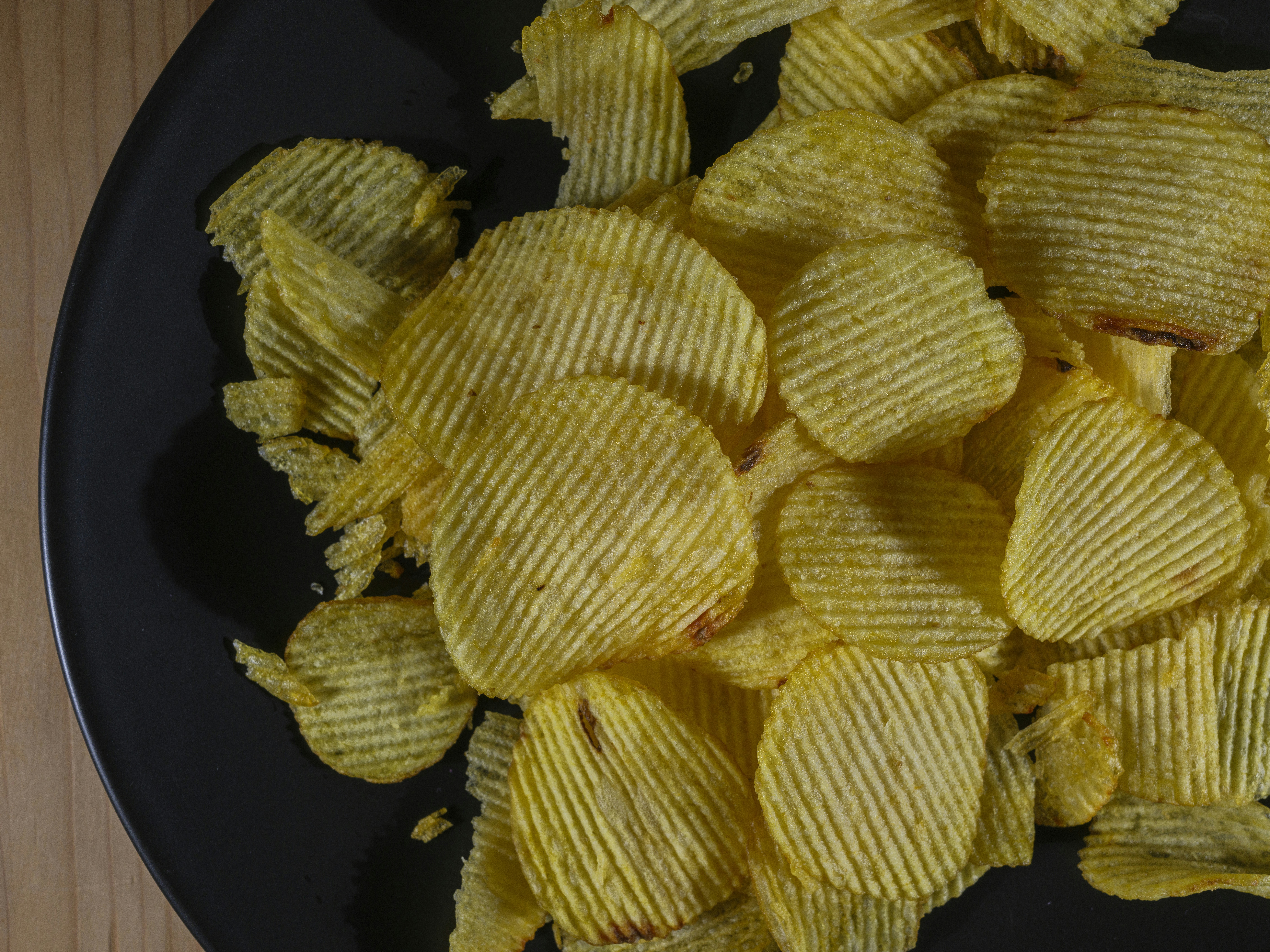 Golden Crisps: Sunlit Potato Chips Piled in a Dark Plate