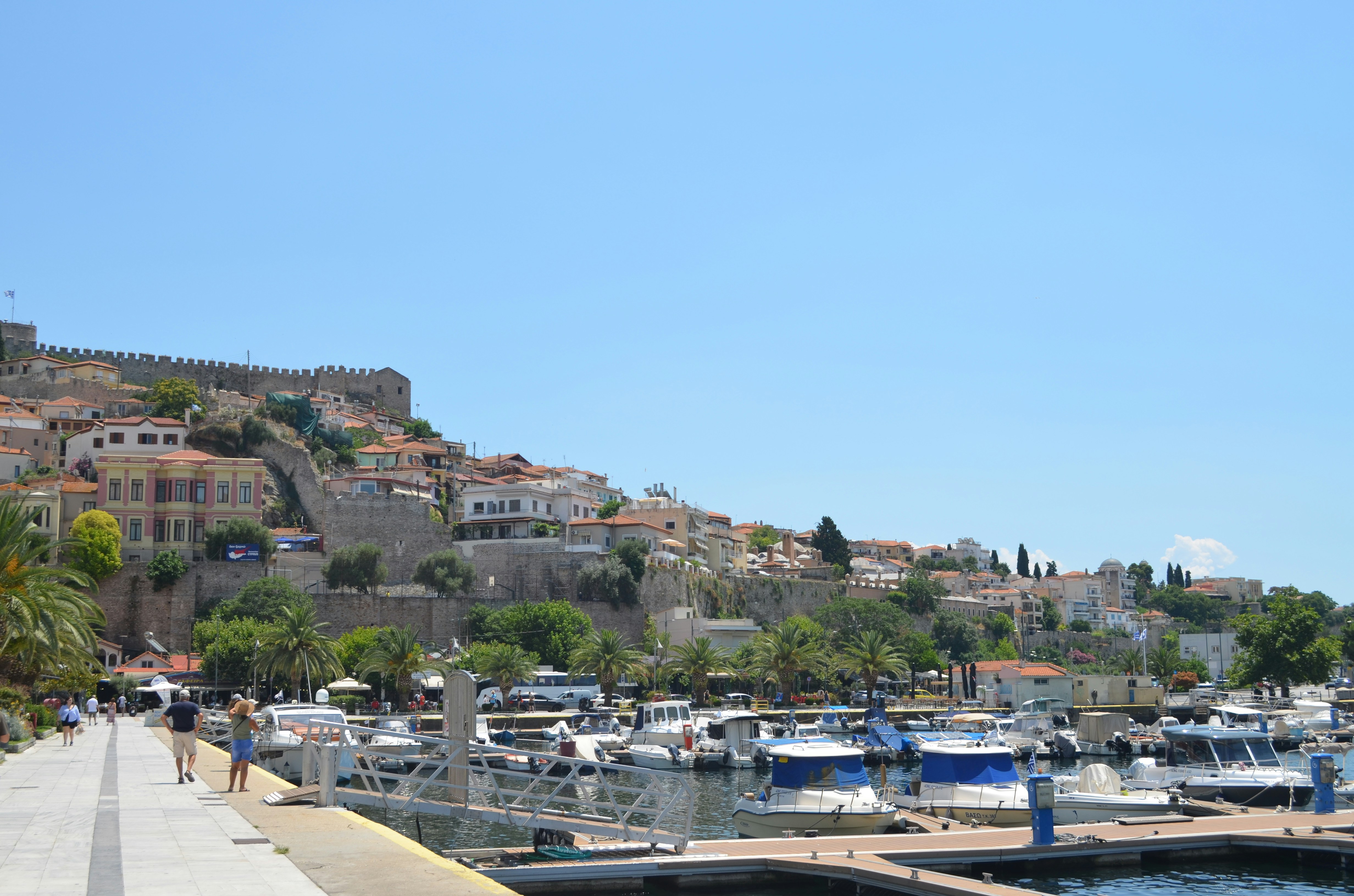 Harbor town in sunlight: boats, promenade and hillside villas
