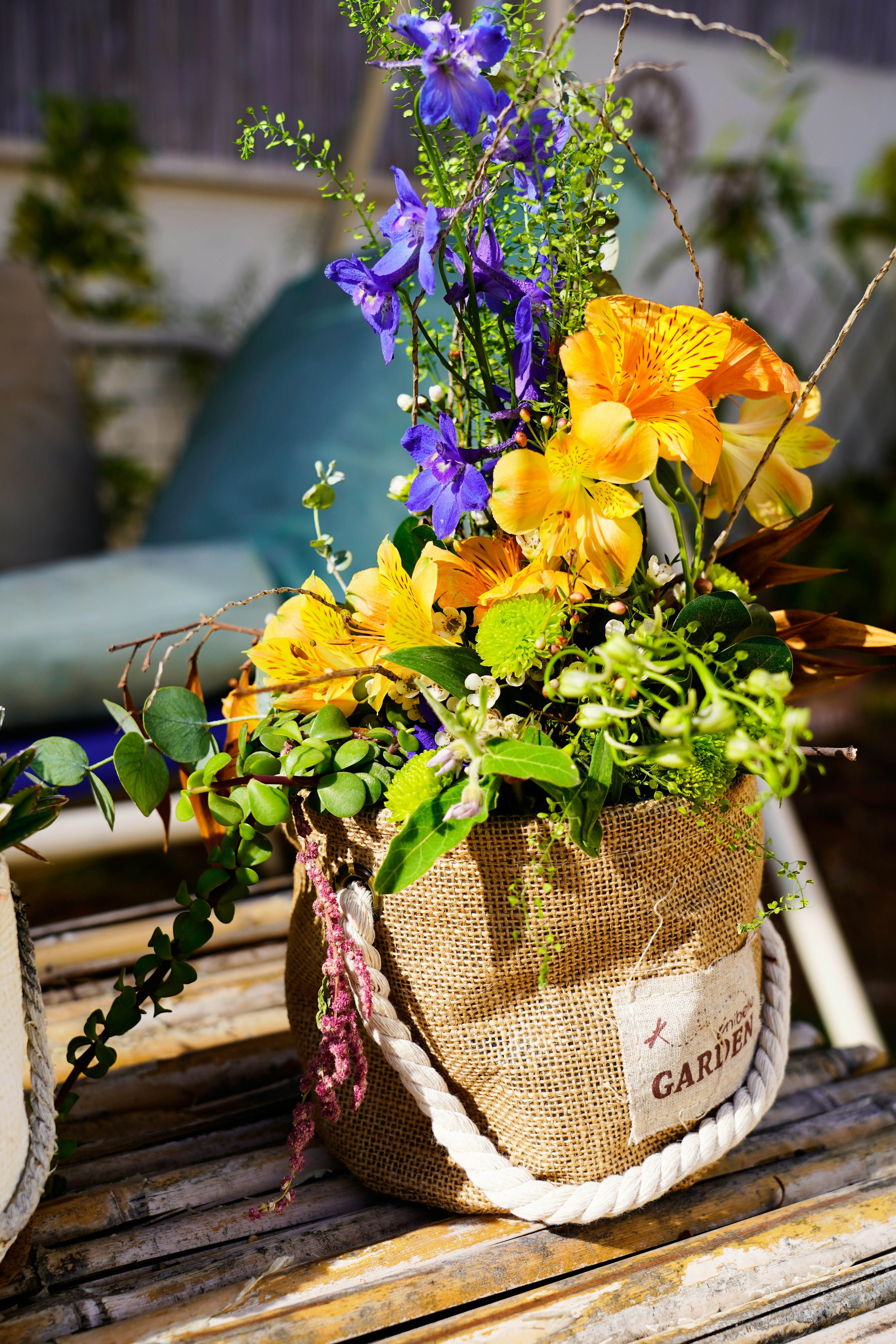 Sunlit Burlap Bloom: A Basket of Vibrant Spring Arrangement