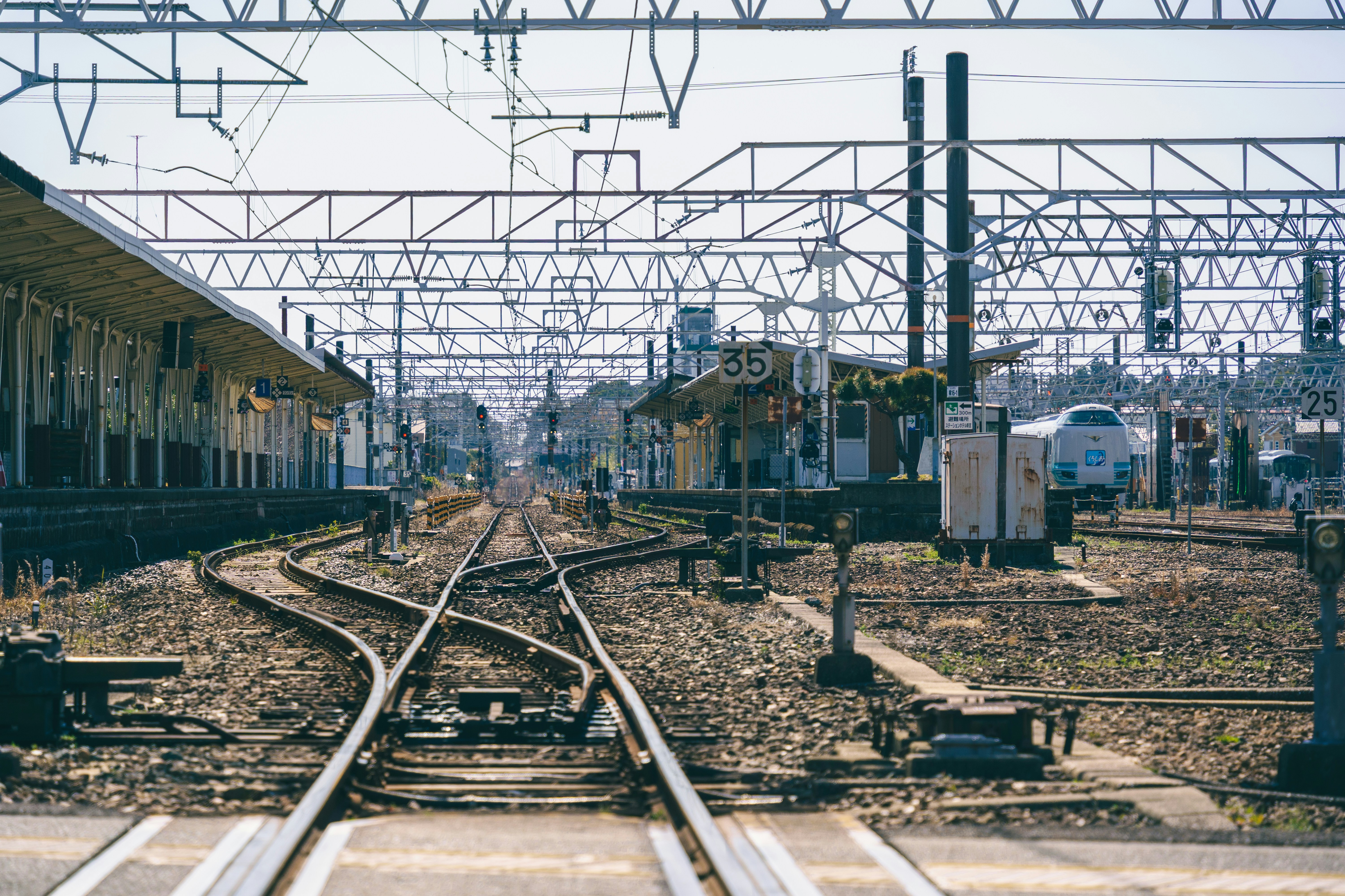 Converging train tracks lead to a station platform.