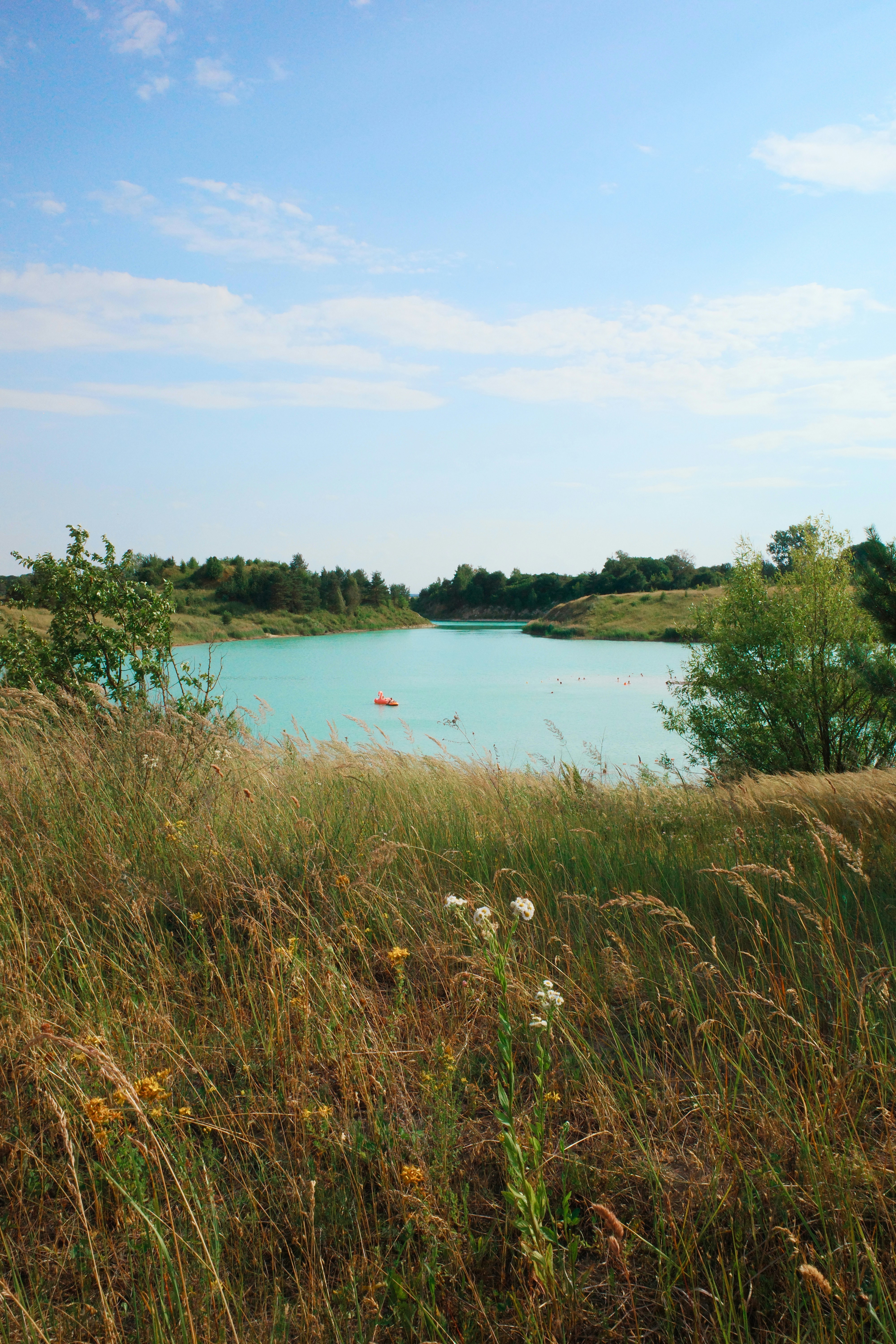 Turquoise Lake Amid Meadowed Banks under a Wide Sky