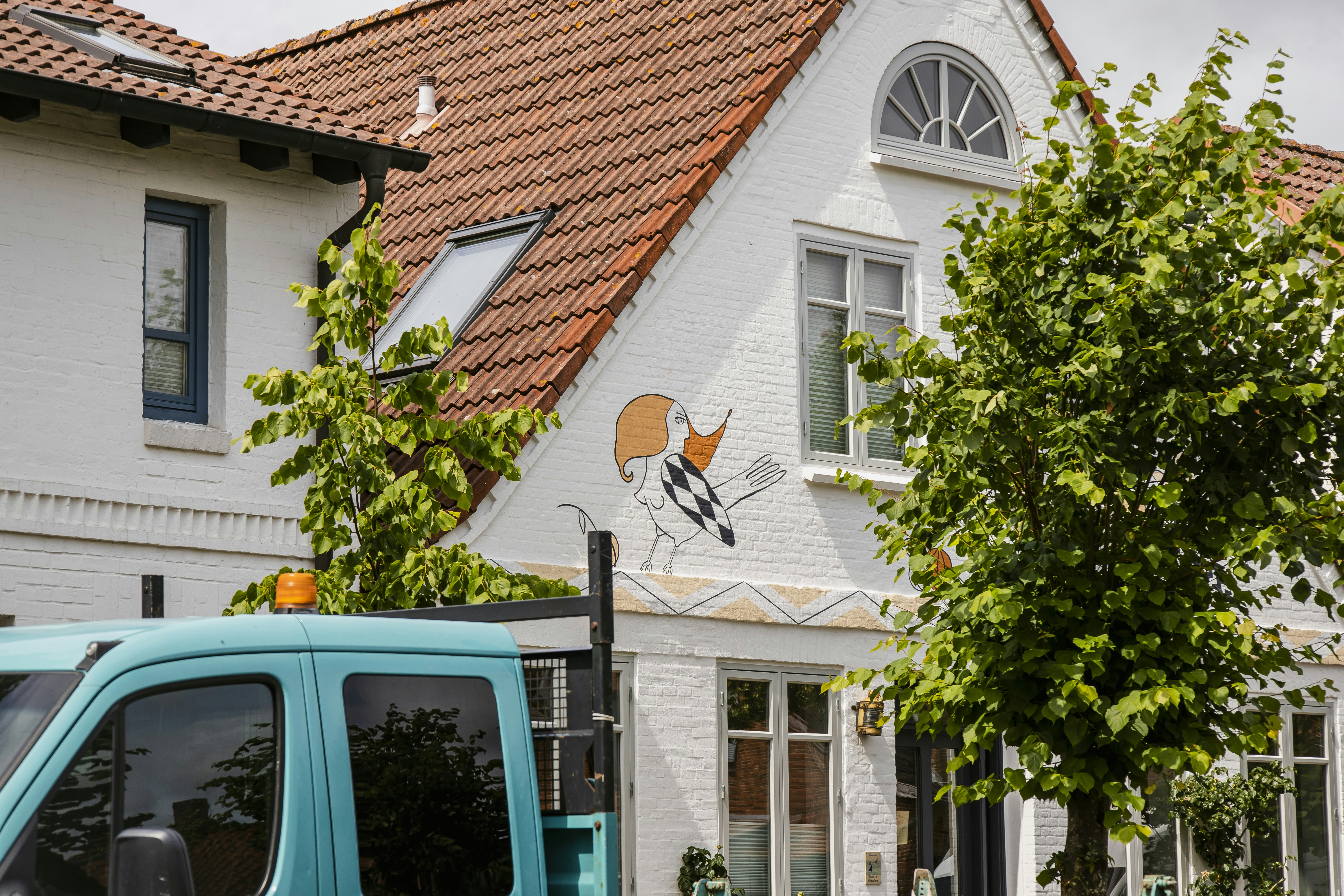 Sunny Streetfront with Painted Bird Mural and Teal Utility Vehicle