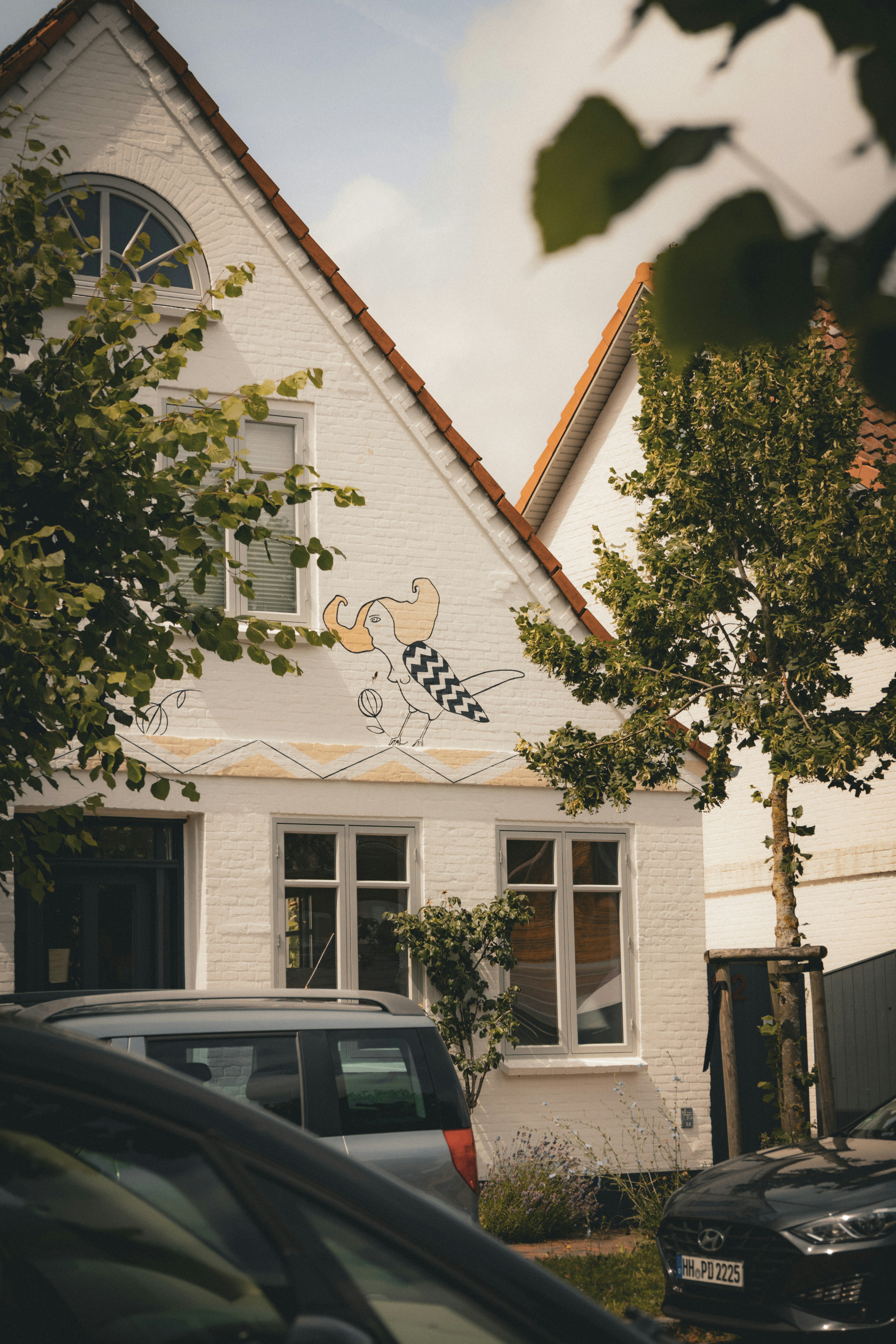 Sunny Whitehouse with Whimsical Mural and Leafy Framing