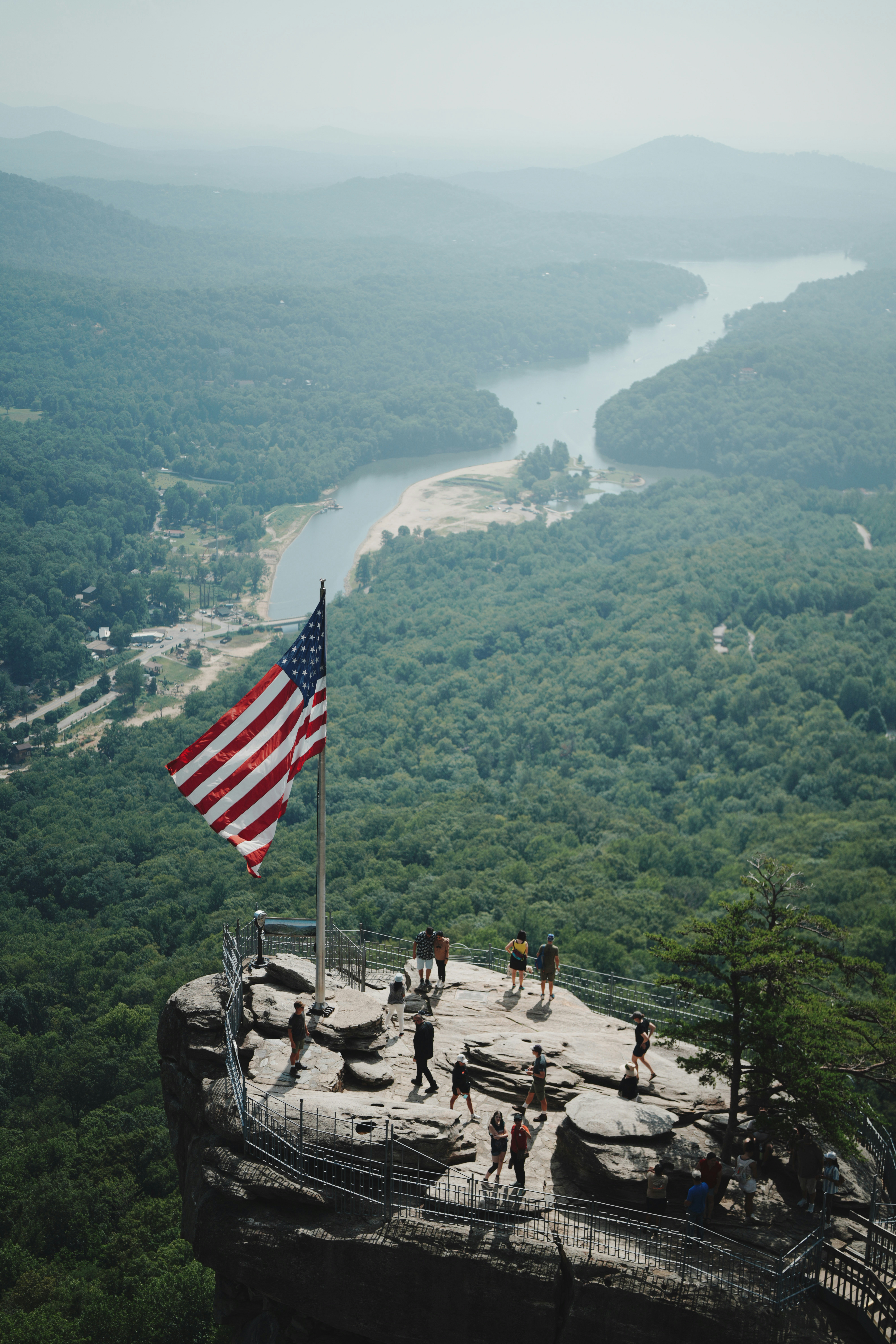 Flag on the Edge: A Summit View Over Verdant Valleys
