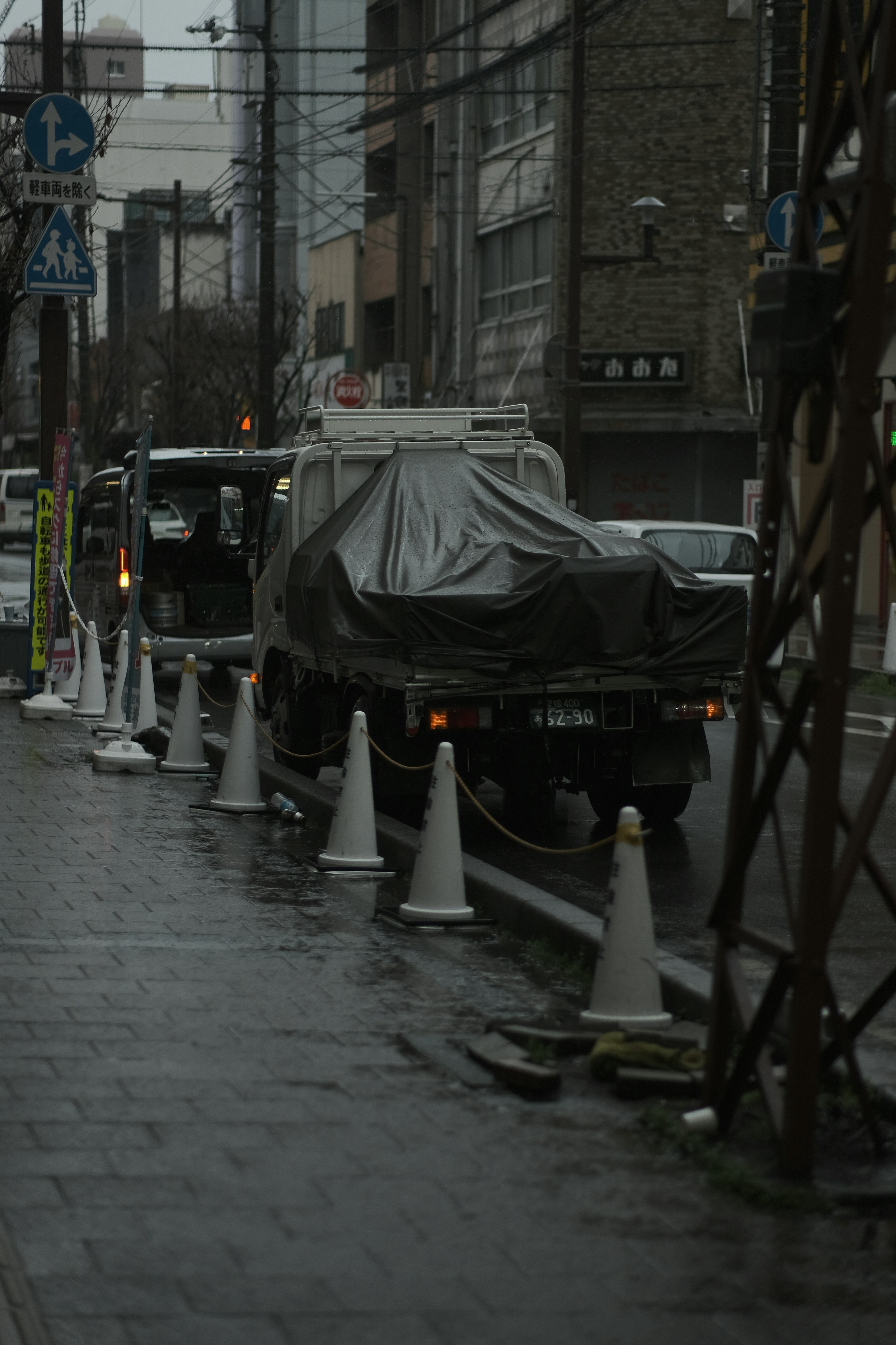 Rain-Slick Street Mission: A Covered Truck Waits Under Neon Dusk