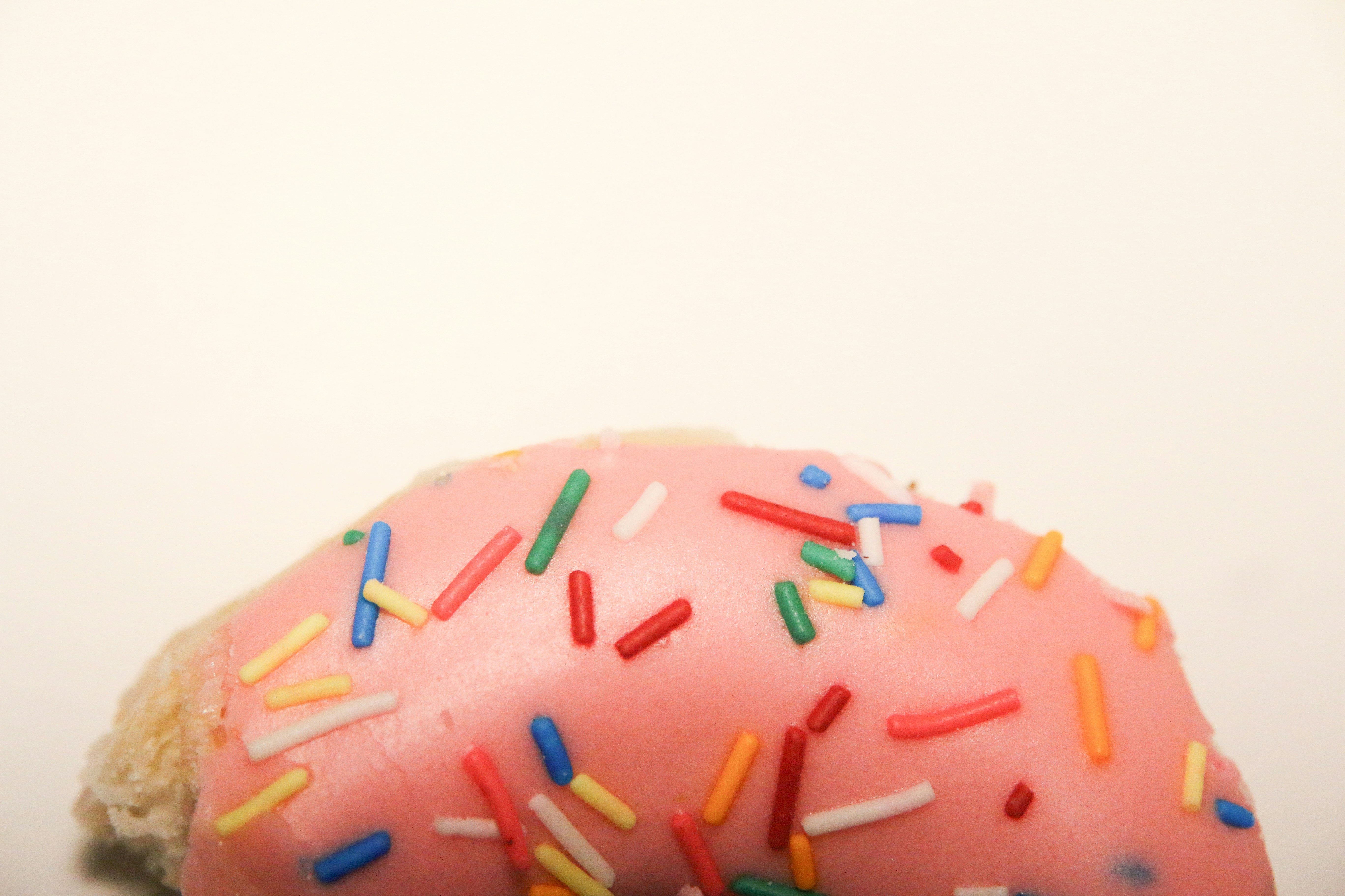 Pink Frosted Donut with Sprinkles Resting at the Edge