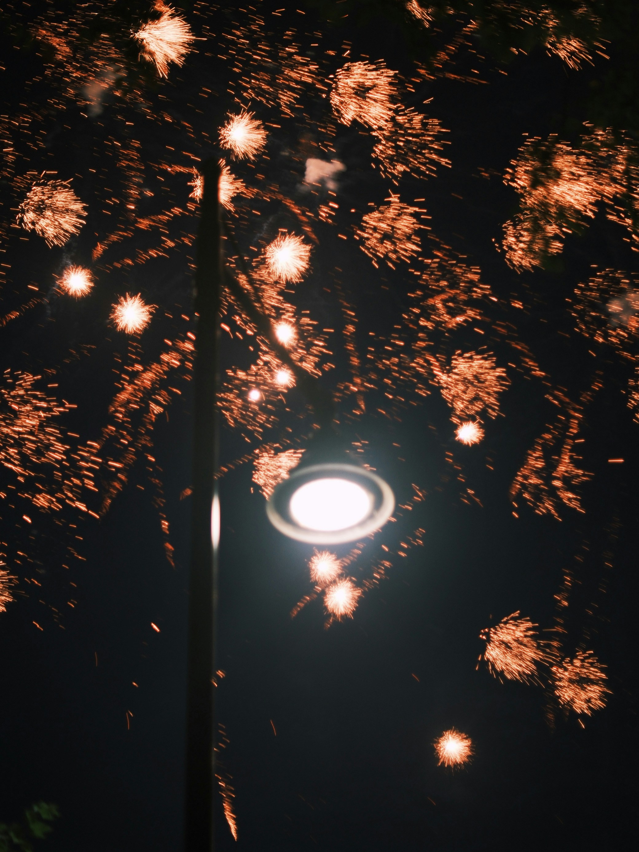 Firework Bloom Above a Quiet Streetlight