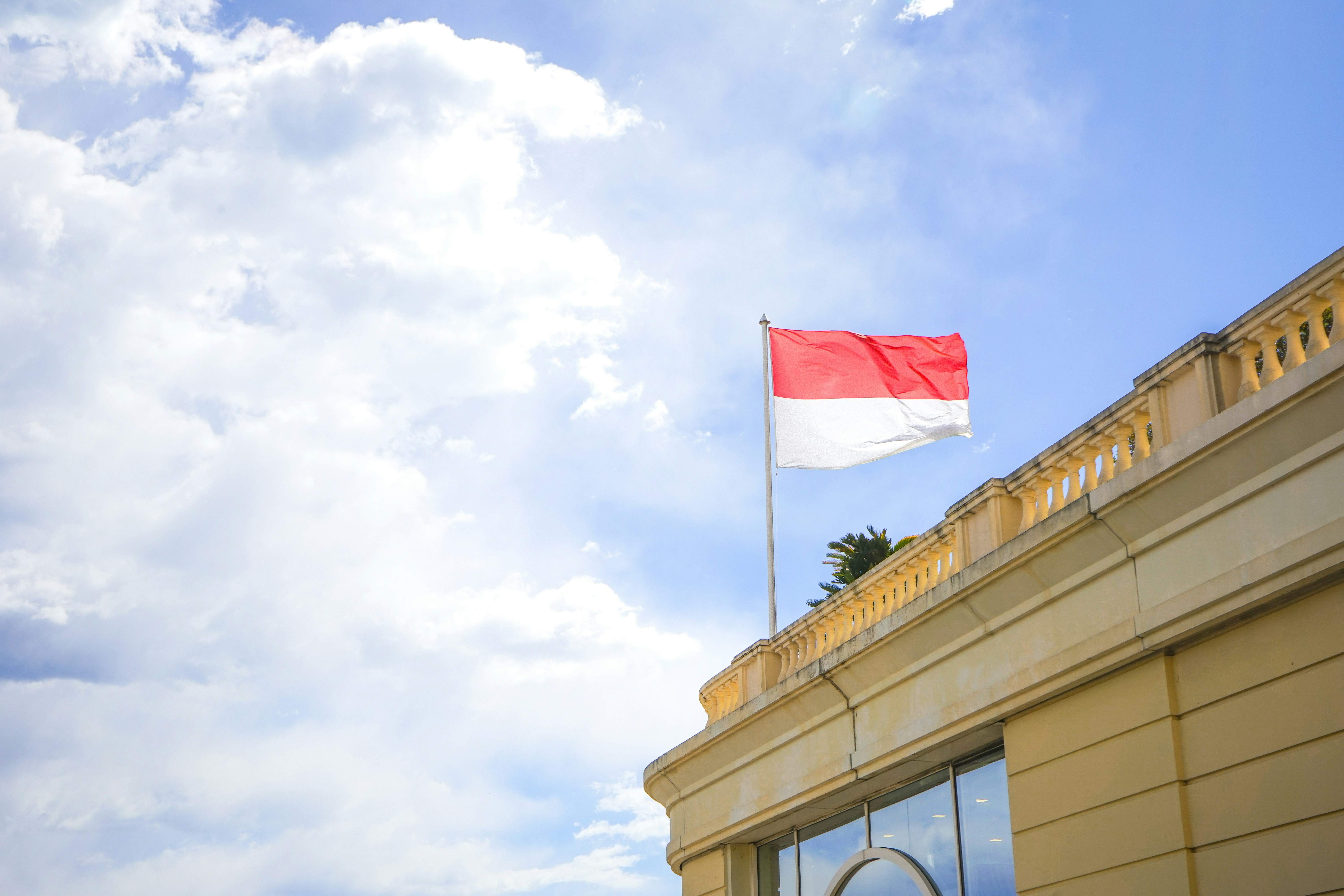 Flag atop a sunlit corner of classical architecture