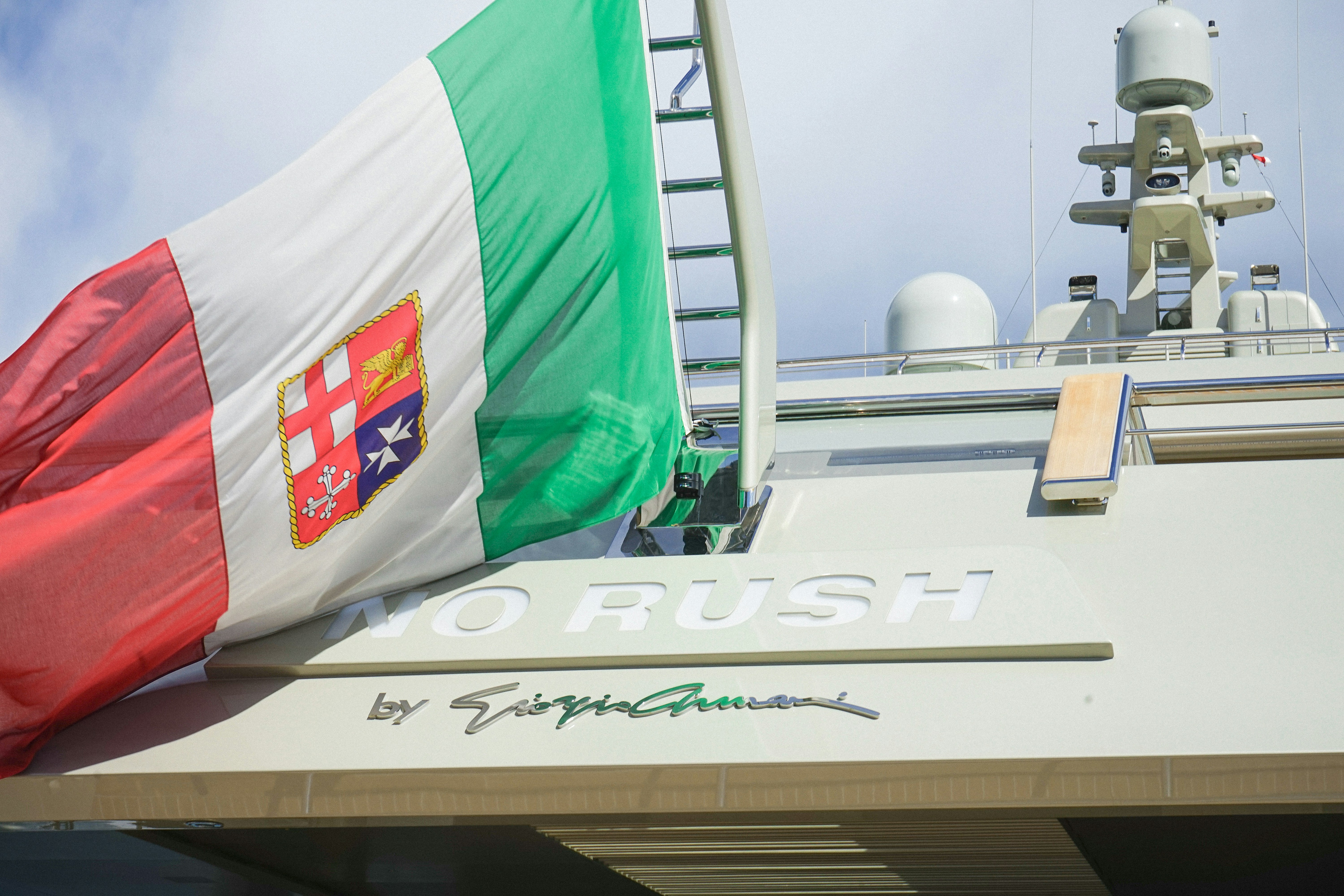 Flag and vessel name framing the deck of a luxury yacht