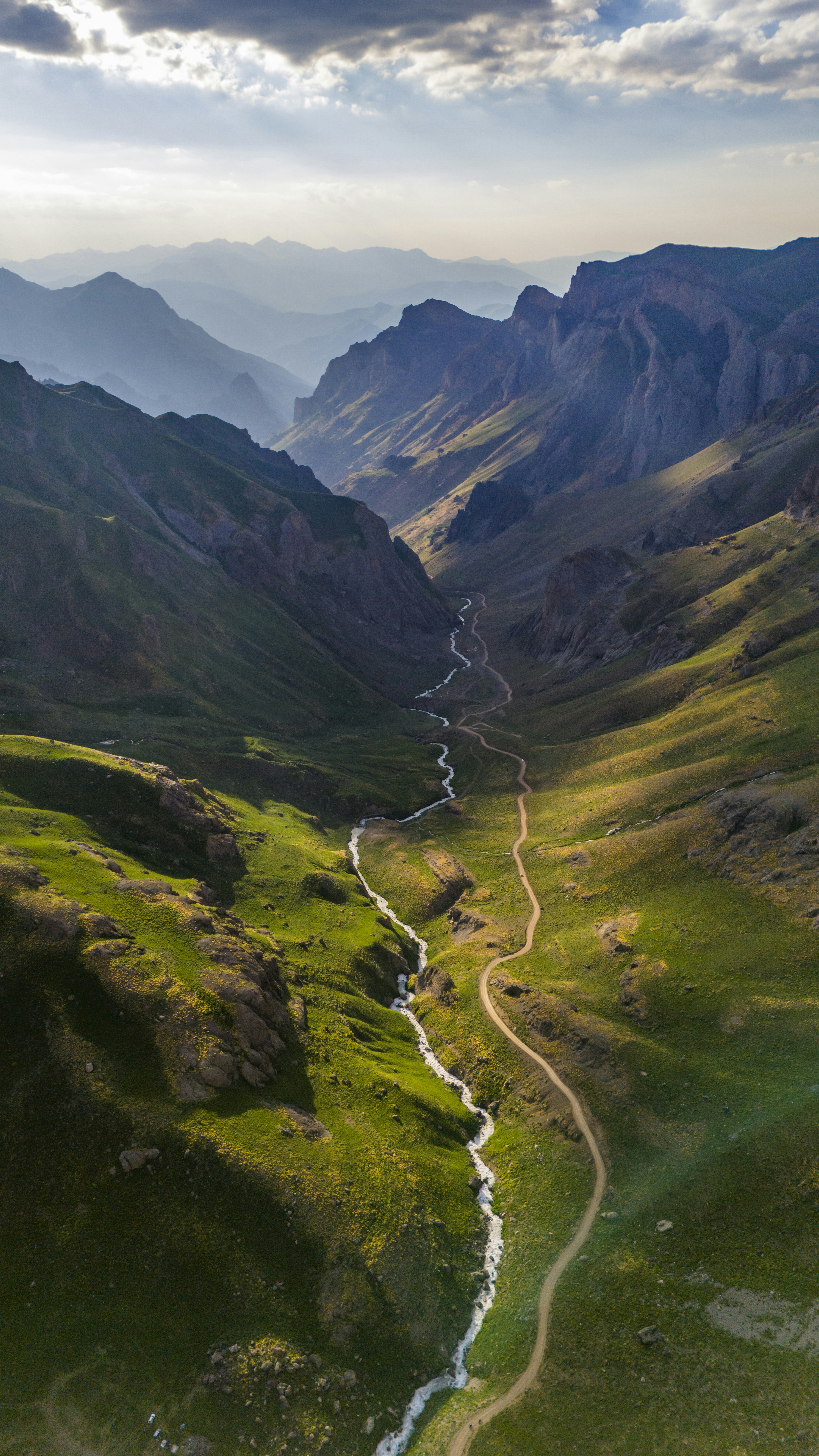 Winding Ribbon: A Valley Path Carved Through Layered Cliffs at Sundown