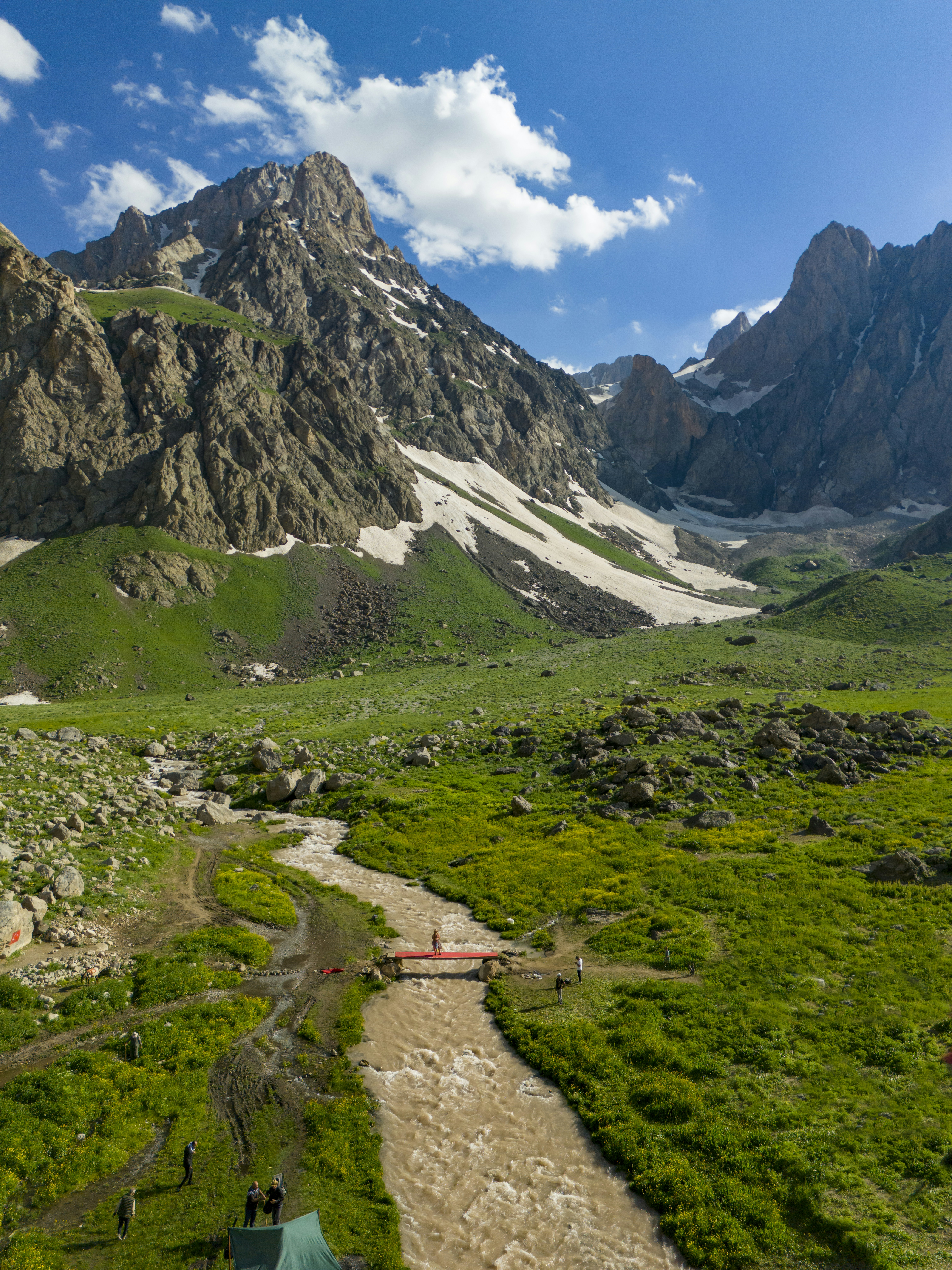Bridge over the alpine channel under jagged peaks