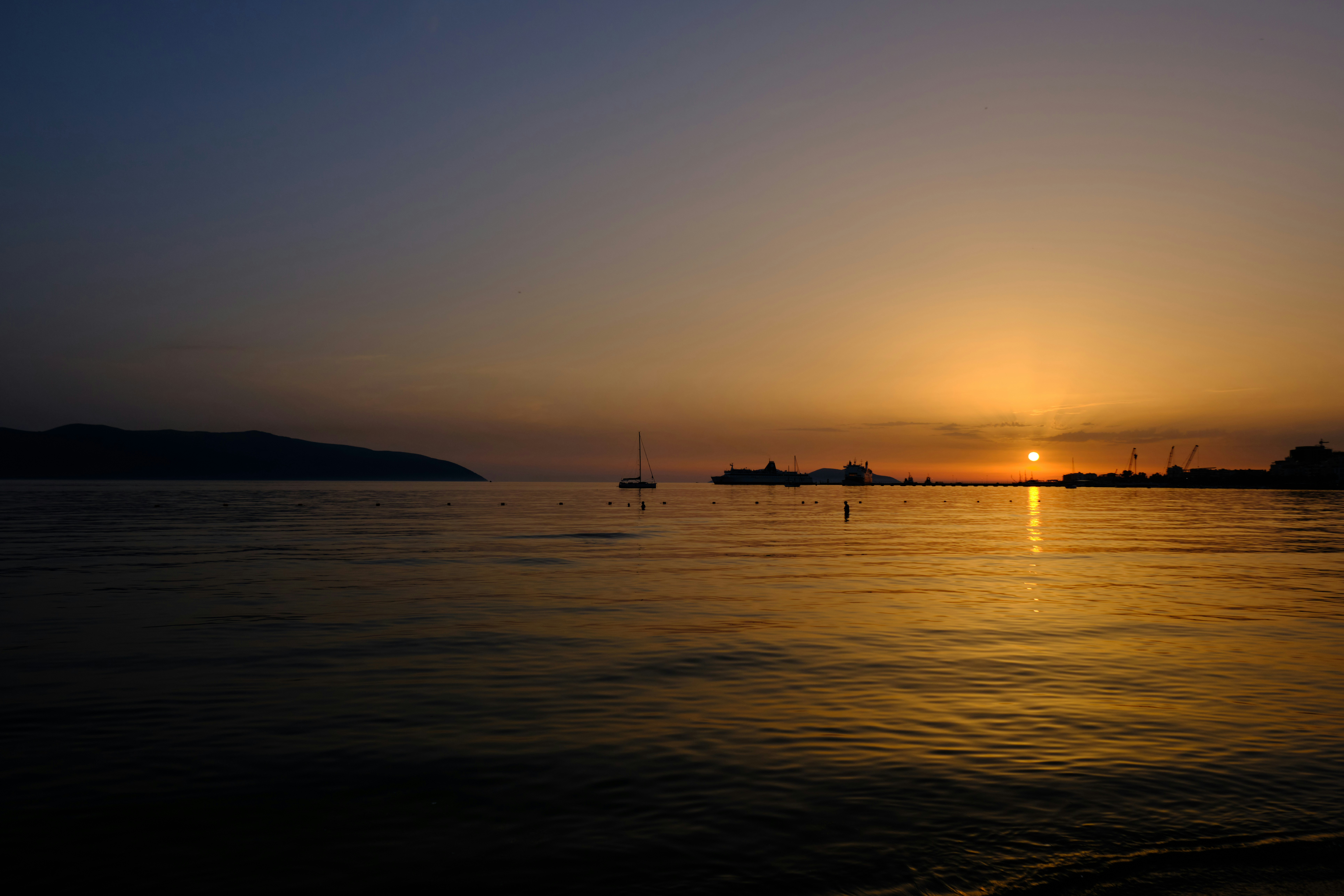 Sunset Horizon: Gentle Waves and a Quiet Marina