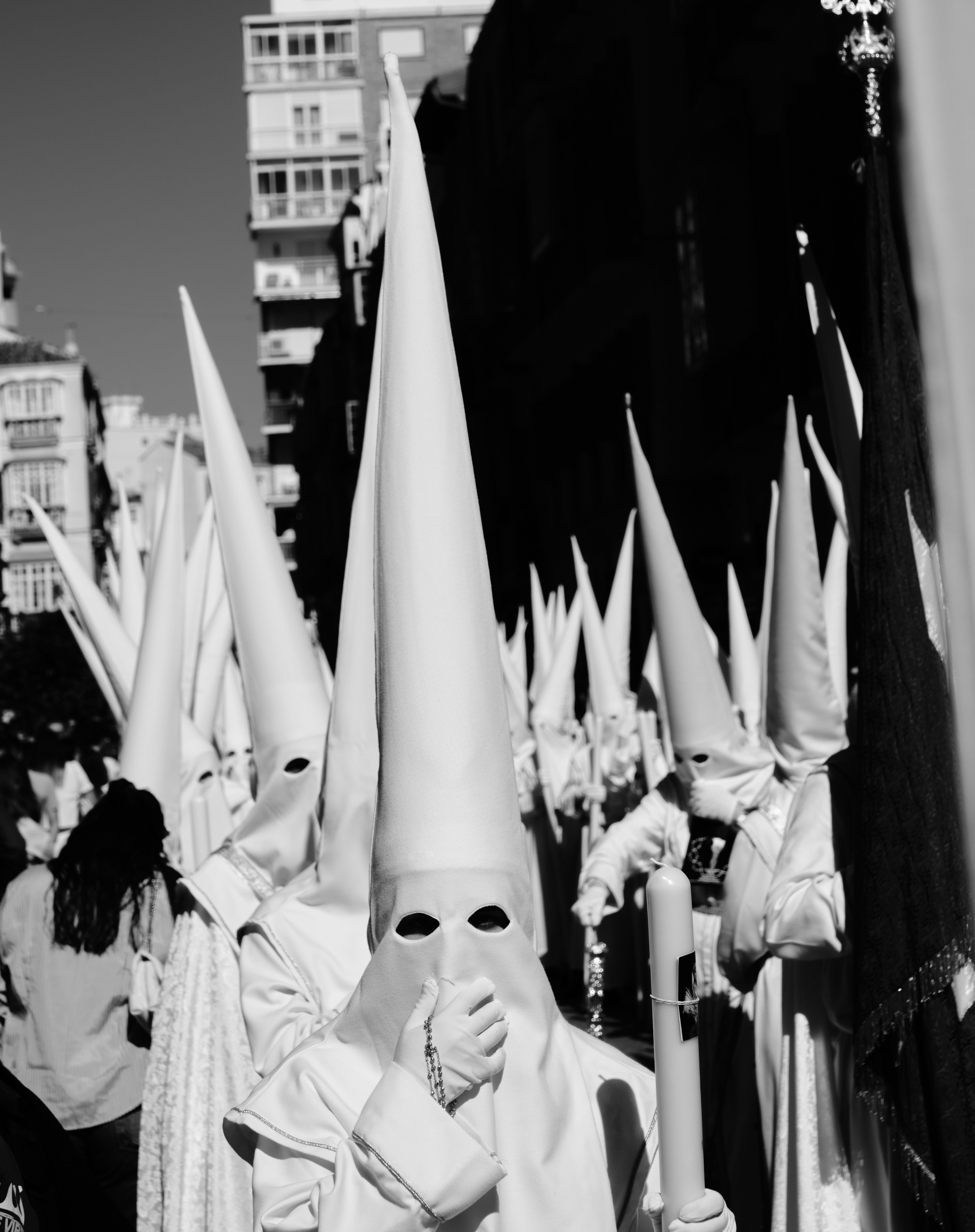 Masked Procession: A Sea of Cone-Hatted Figures marches through a city