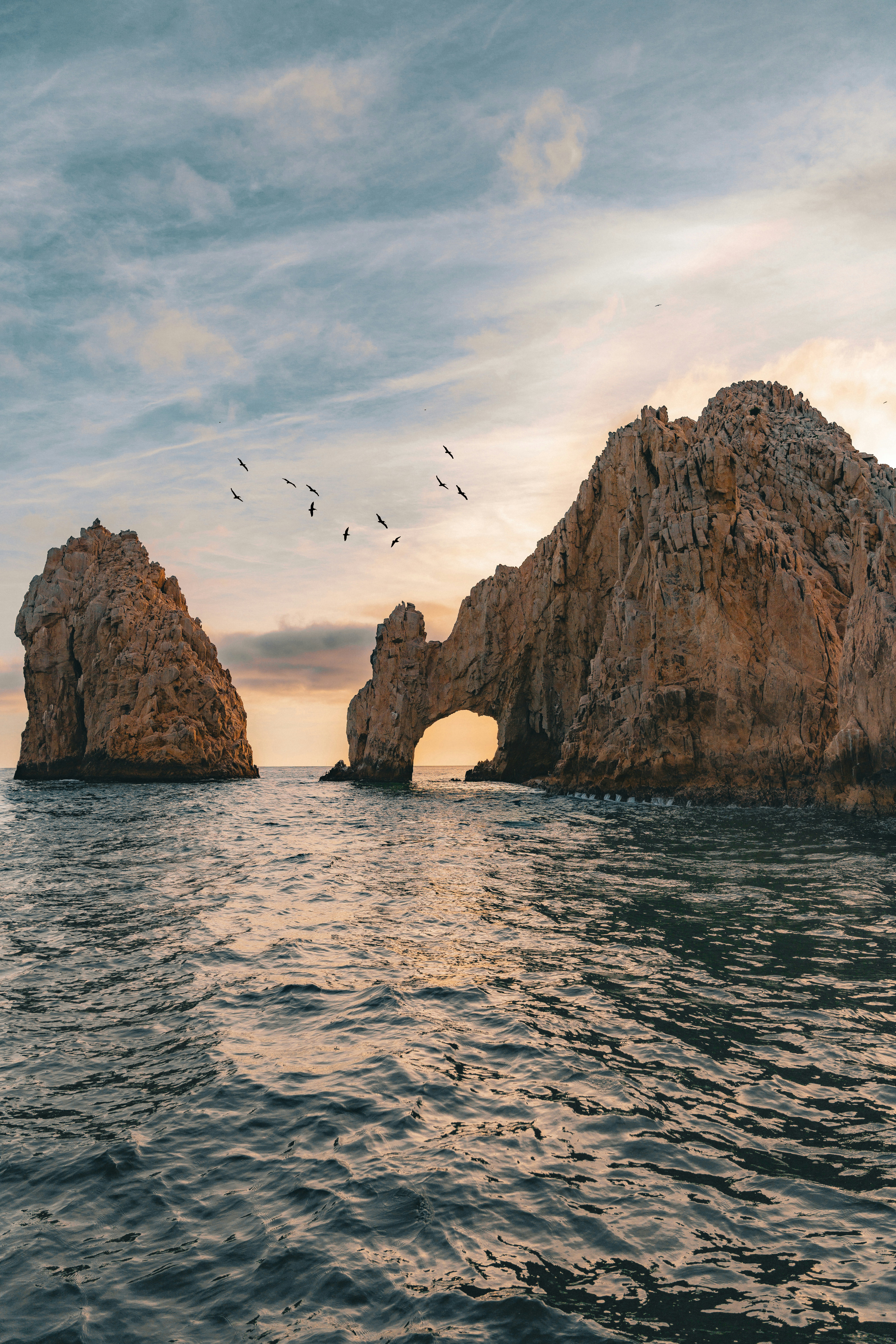 Rugged sea arch at dusk: a flock over jagged cliffs