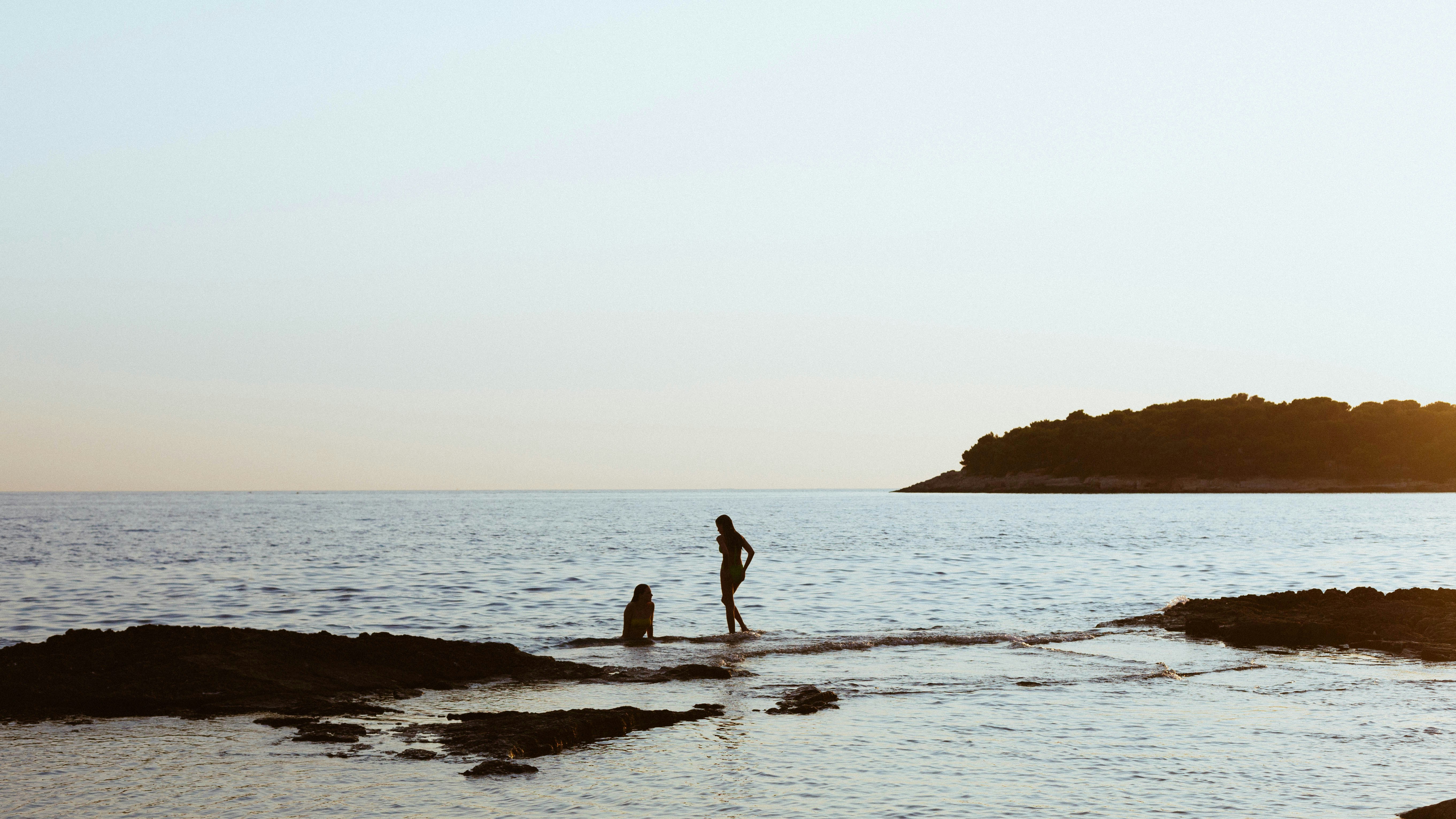 A couple of people are taking an evening swim at a beach in Pula, Croatia.