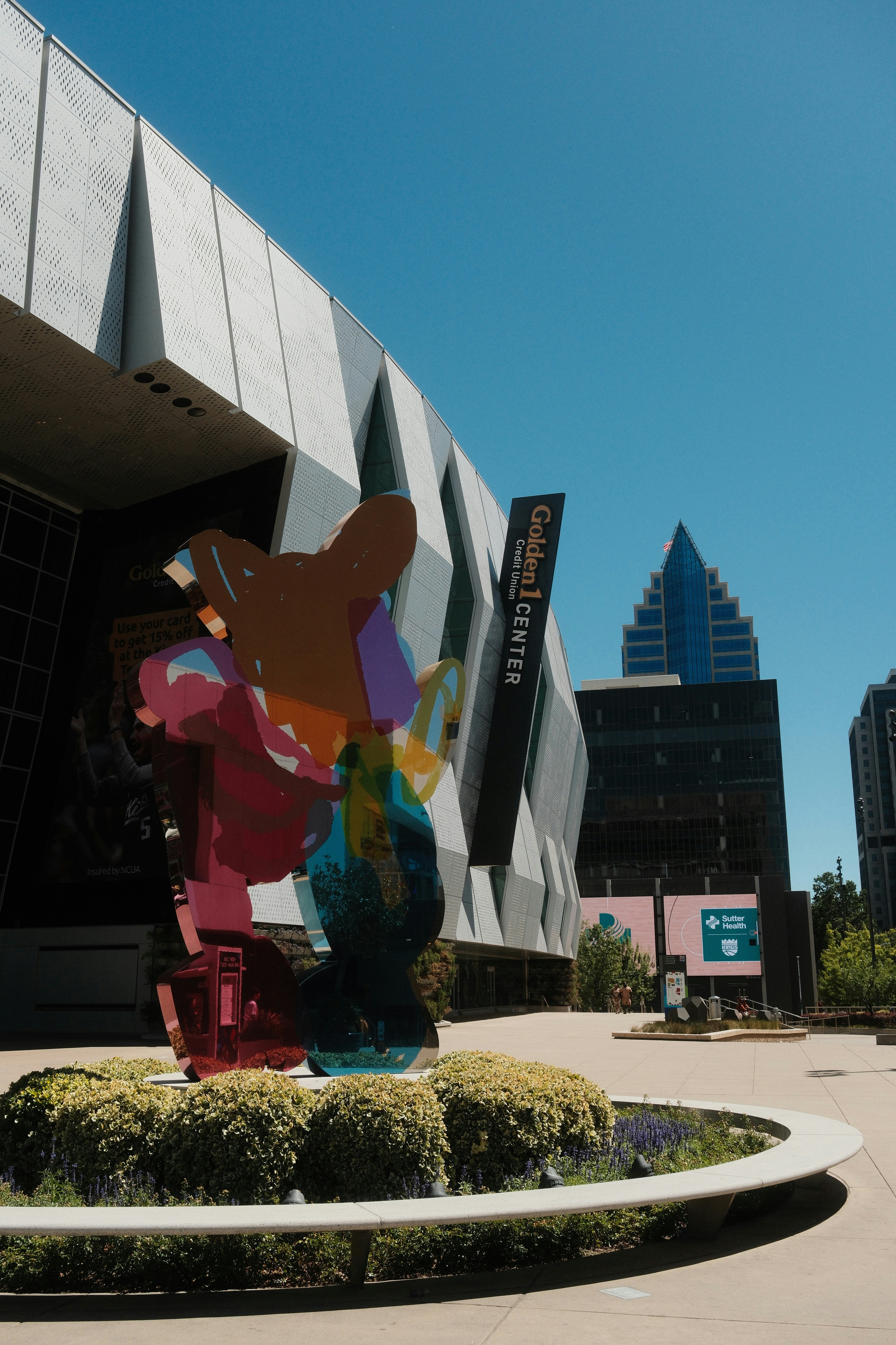 Colorful sculpture anchors a modern plaza beside a bold geometric building