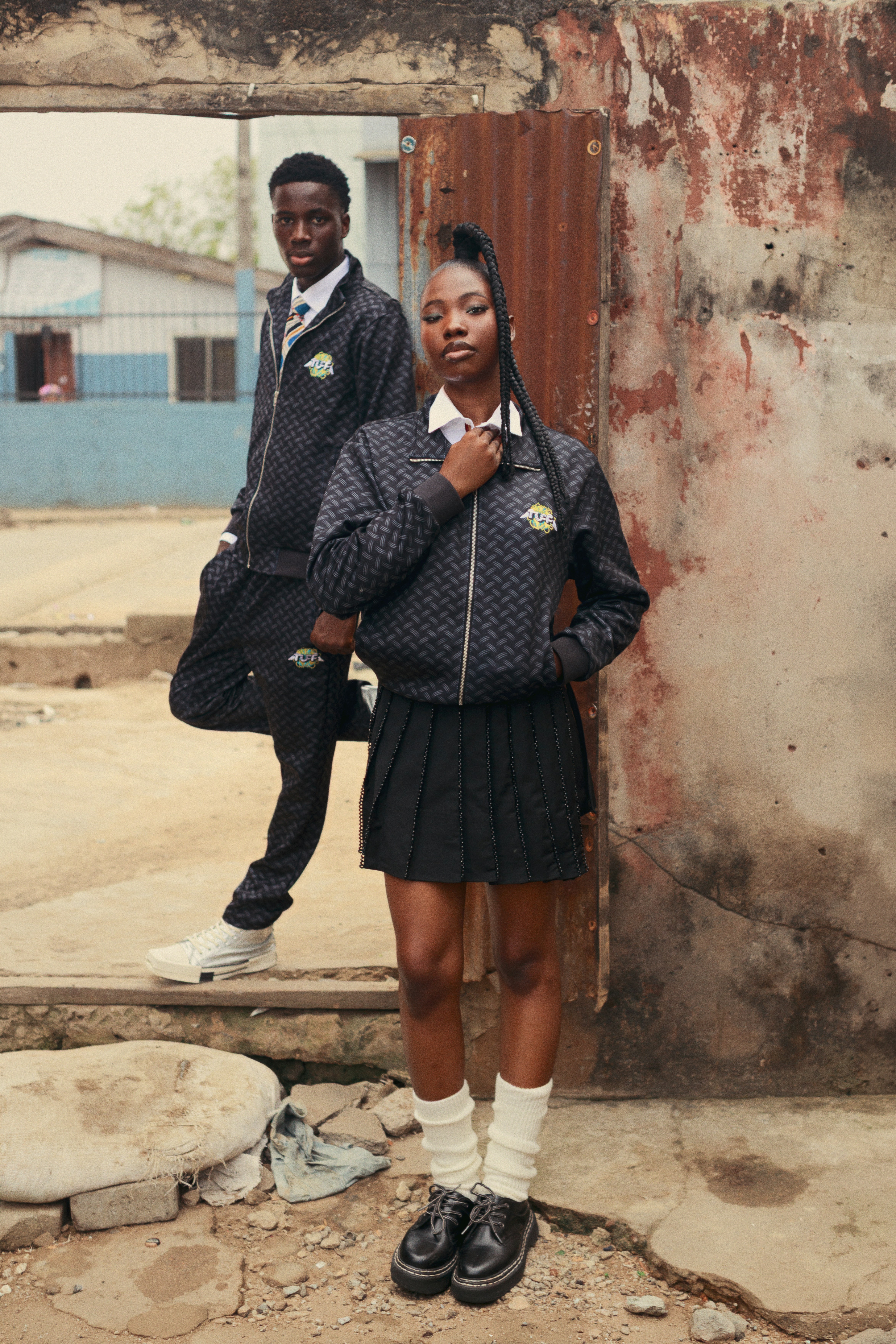Students in coordinated uniforms posing by a weathered wall
