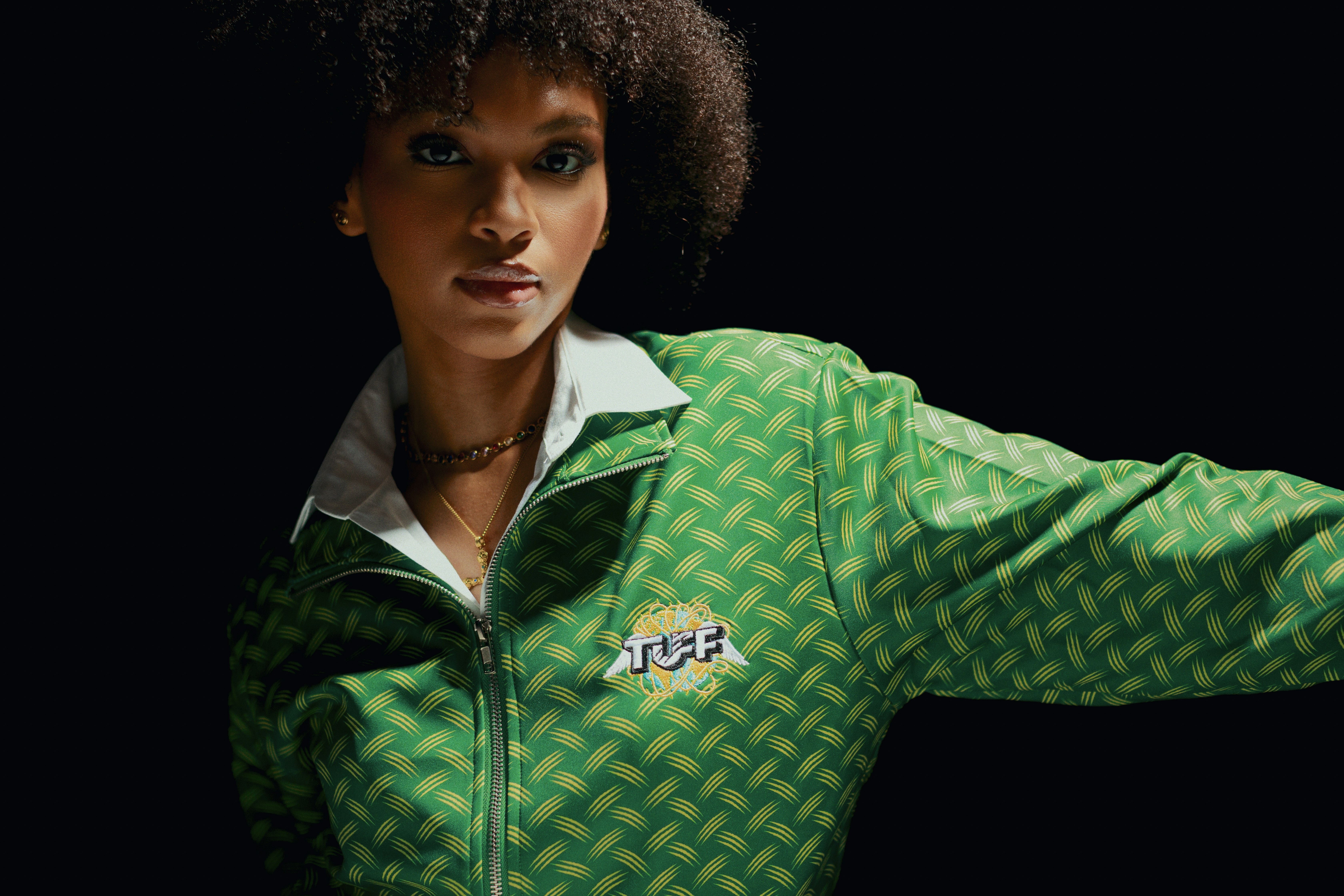 Green patterned jacket with athletic emblem against dark studio backdrop
