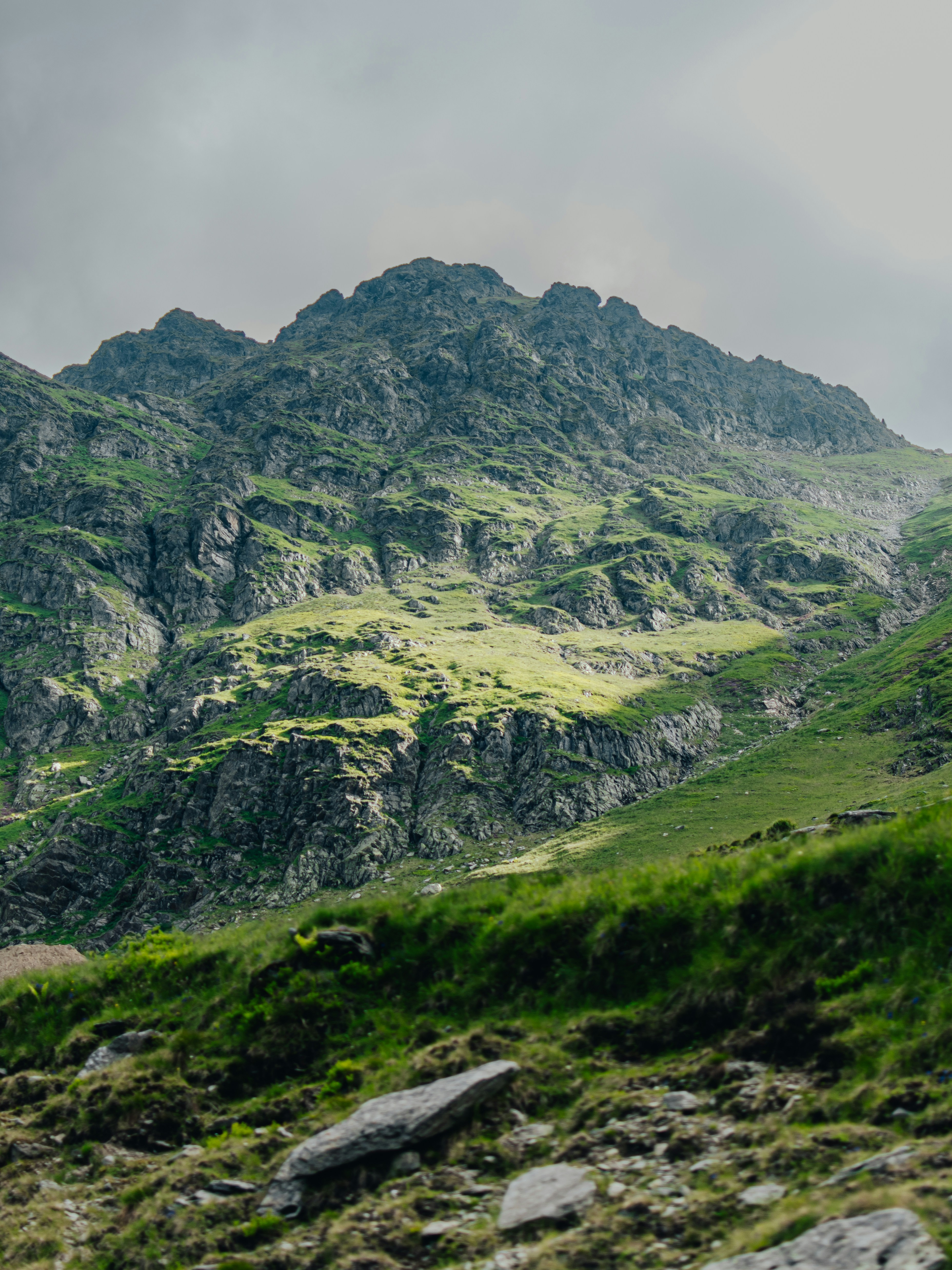 Green-tinted Ridge: A Rugged Ascent Beneath Cloudy Skies