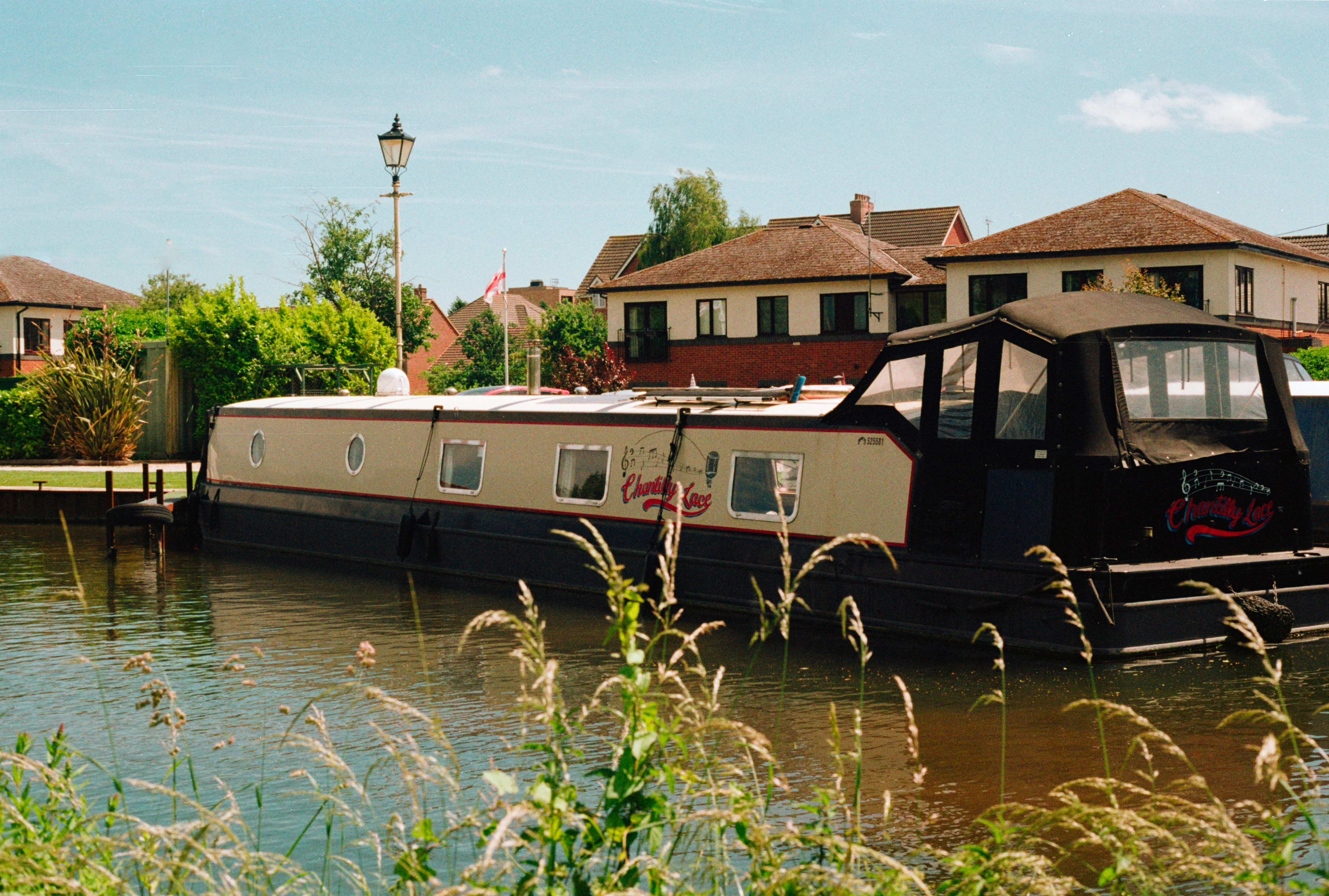 Sunlit Canal Narrowboat moored beside a riverside village