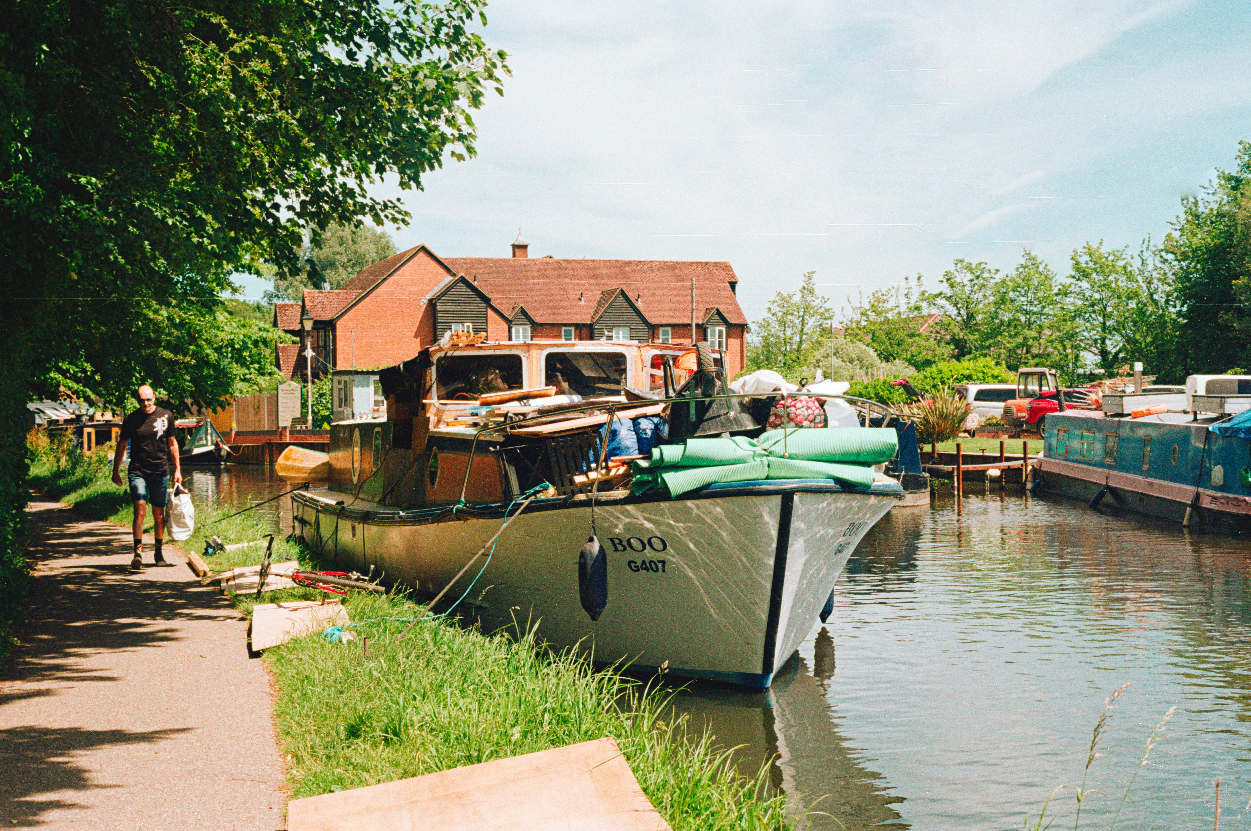 Boats Docked Along a Sunlit Canal with Red Brick Homes