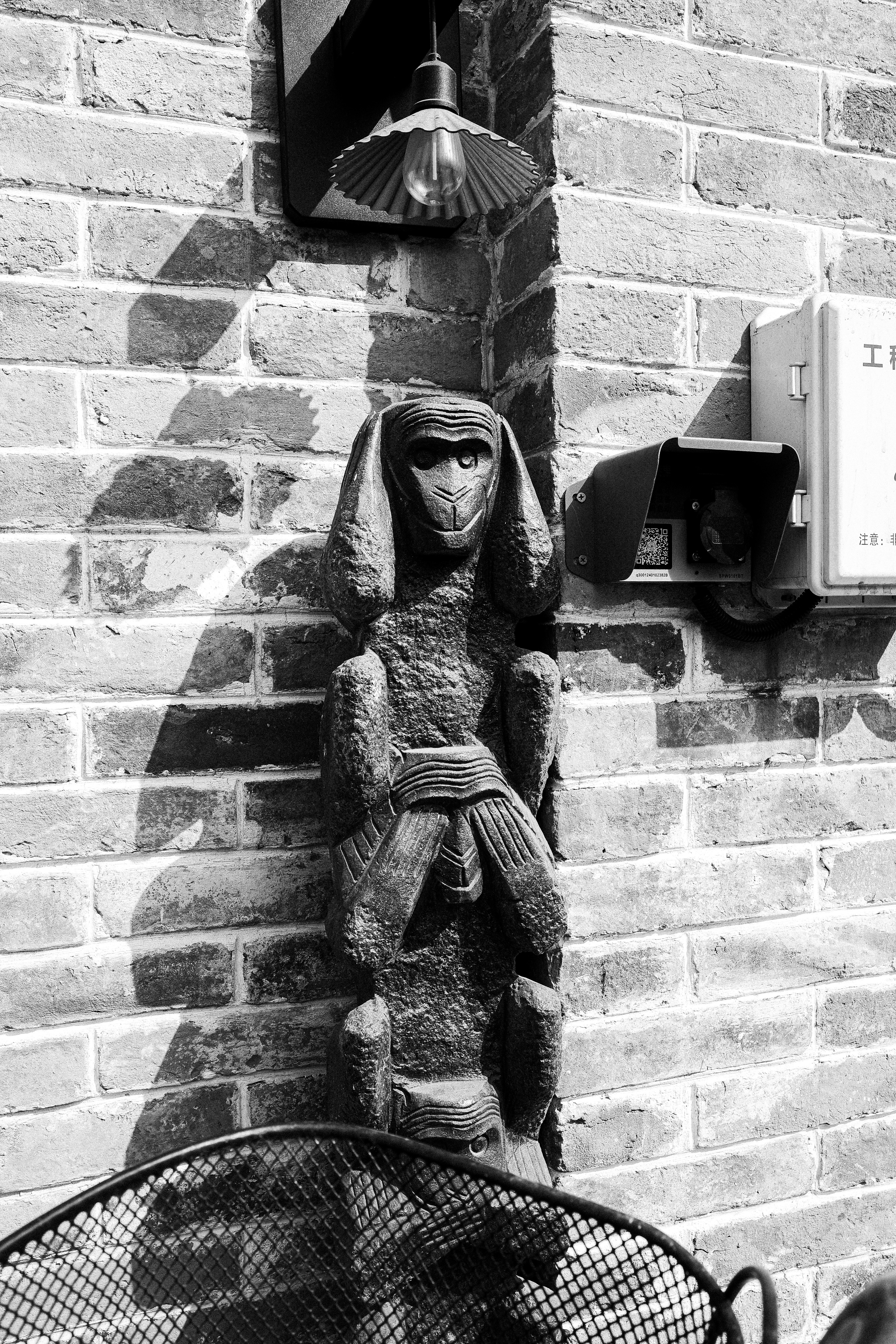 Stone Monkey by the Brick Wall: A Quiet, Shadowed Figure