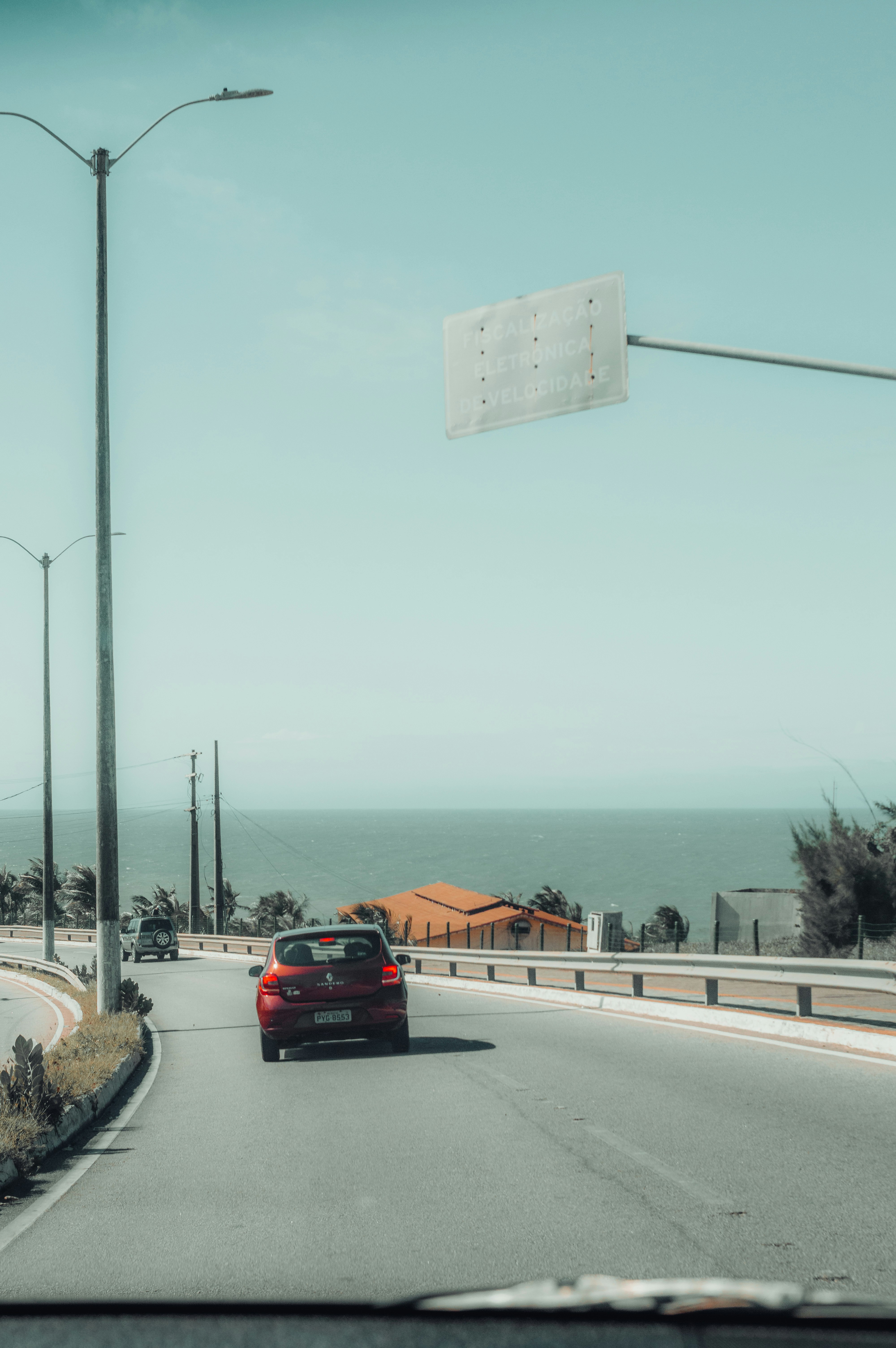 Coastal Drive: Red Hatchback Crossing the Horizon