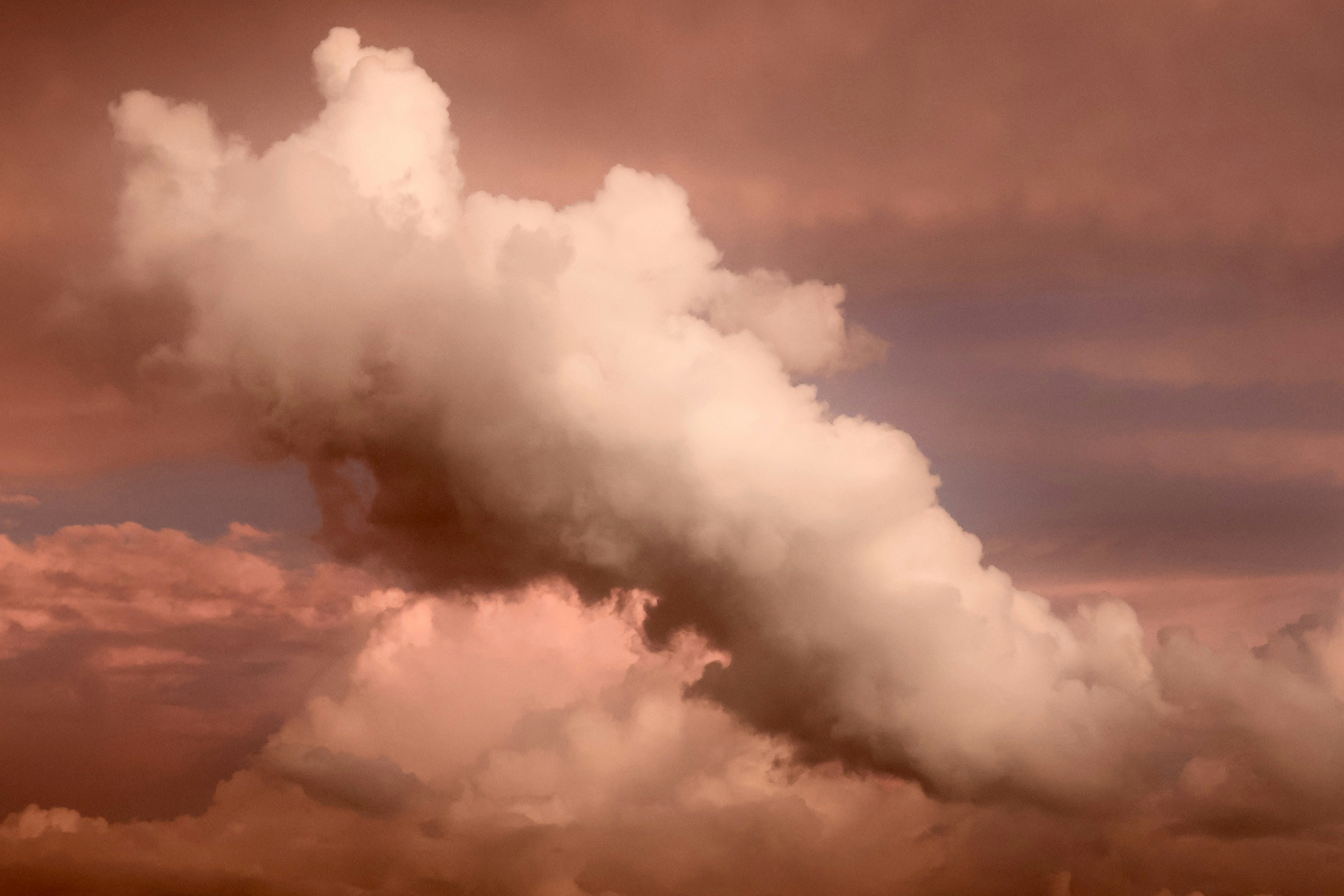 Soft, billowing cloud plume drifting across a warm, sunset-tinged sky with subtle gradient tones. A minimal, atmospheric study of vapor against color-rich clouds.