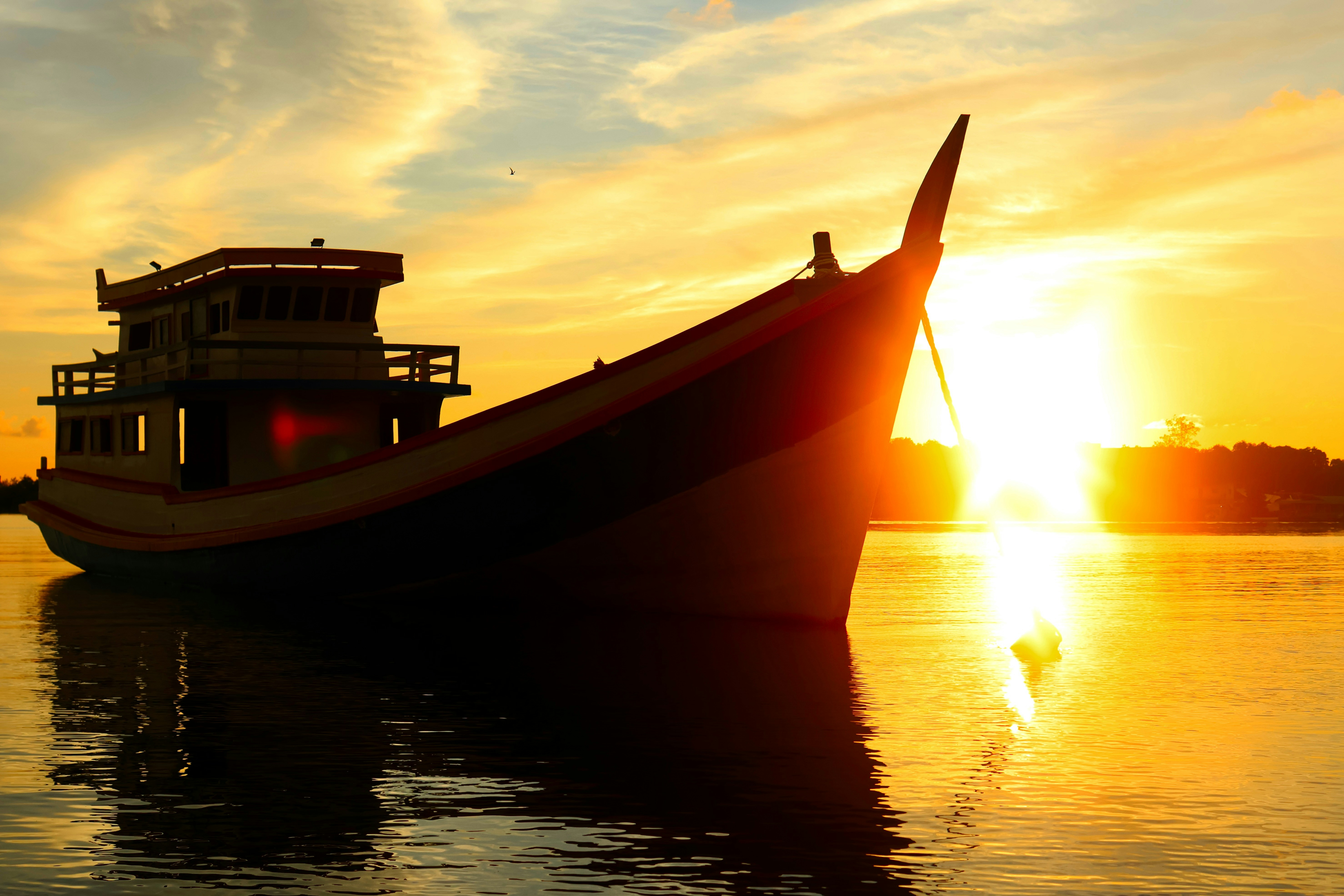 Sunlit Vessel at Dusk: A Silent Voyage Amid Golden Waves