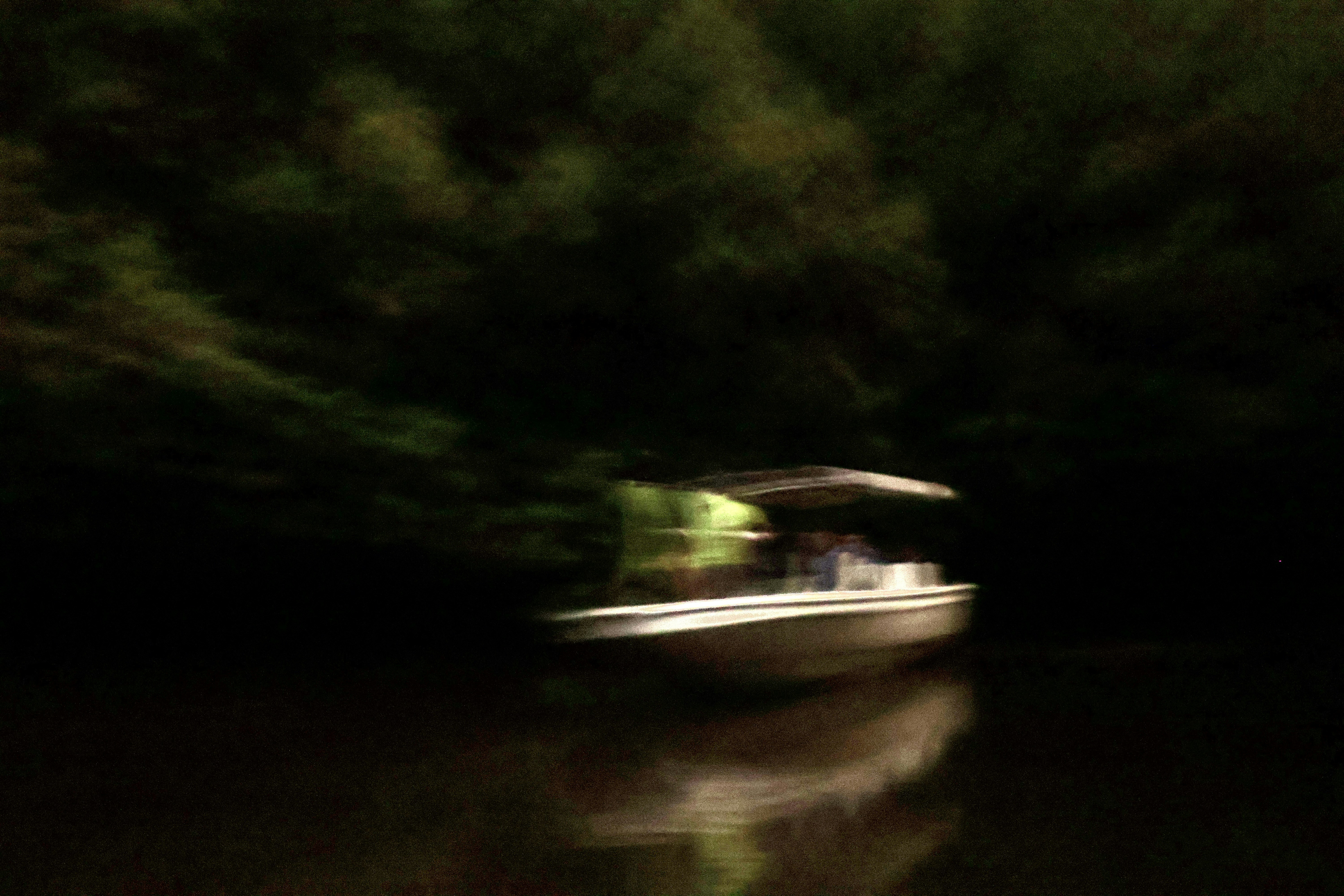Moonlit boat glide: a blurred night scene along a riverbank