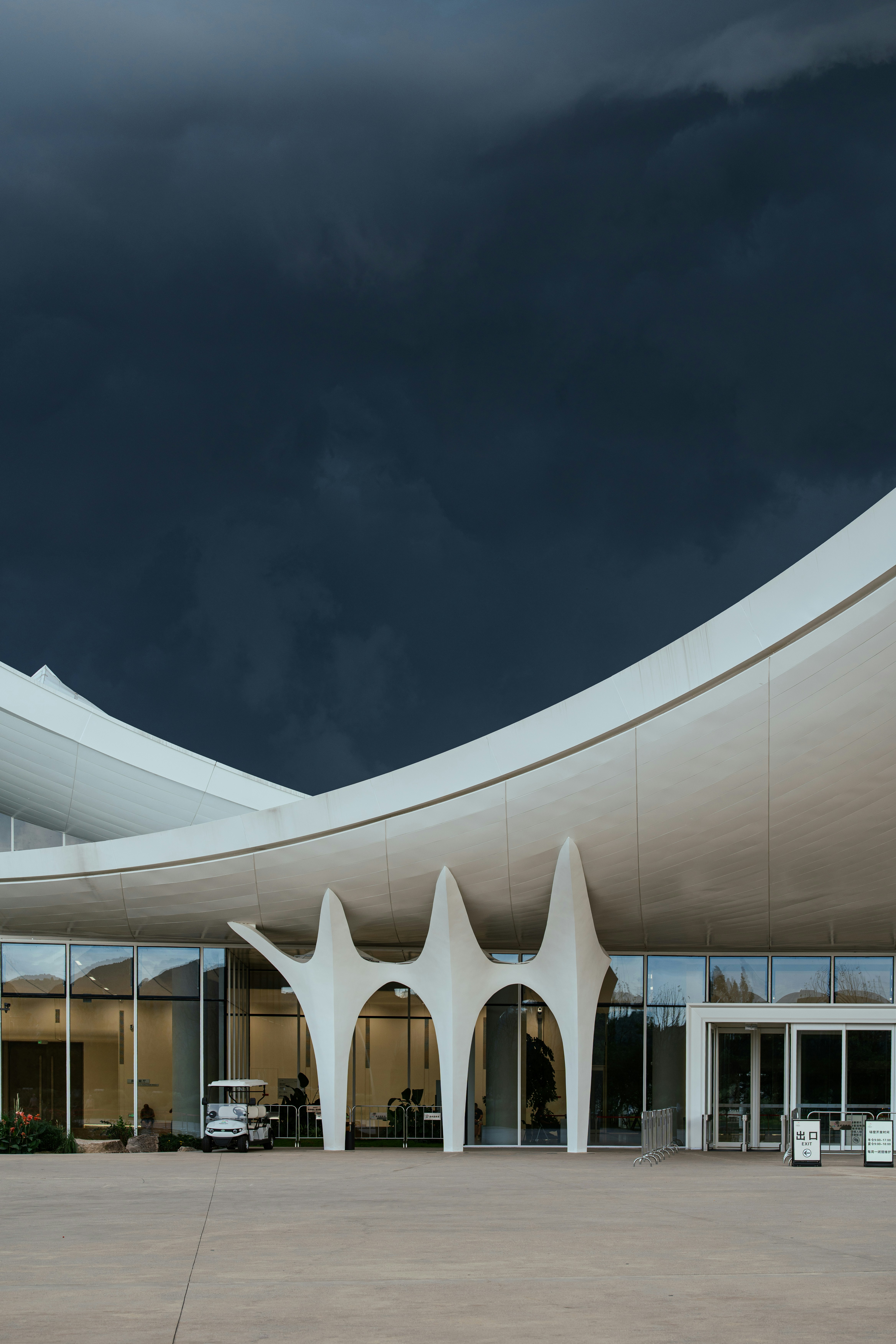 Curved modern facade under a stormy sky
