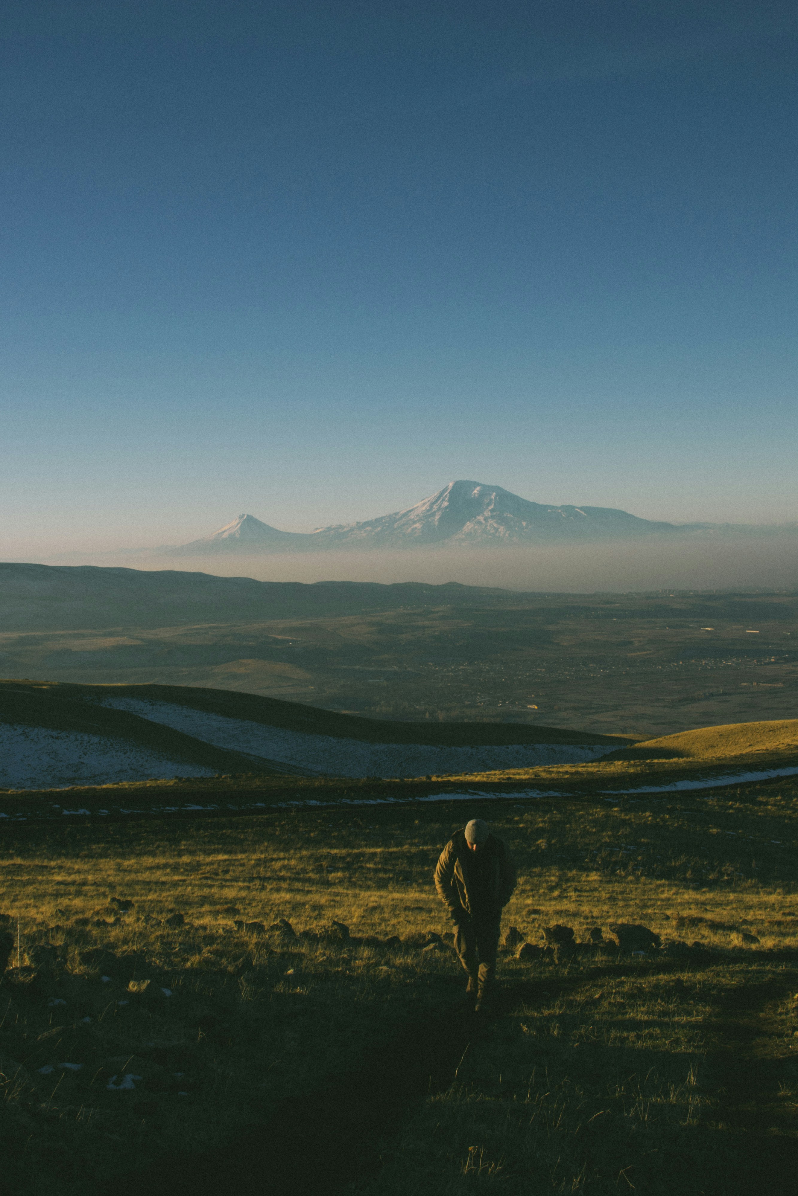 Lonely Wanderer Beneath Snow-Kissed Peaks at Dusk