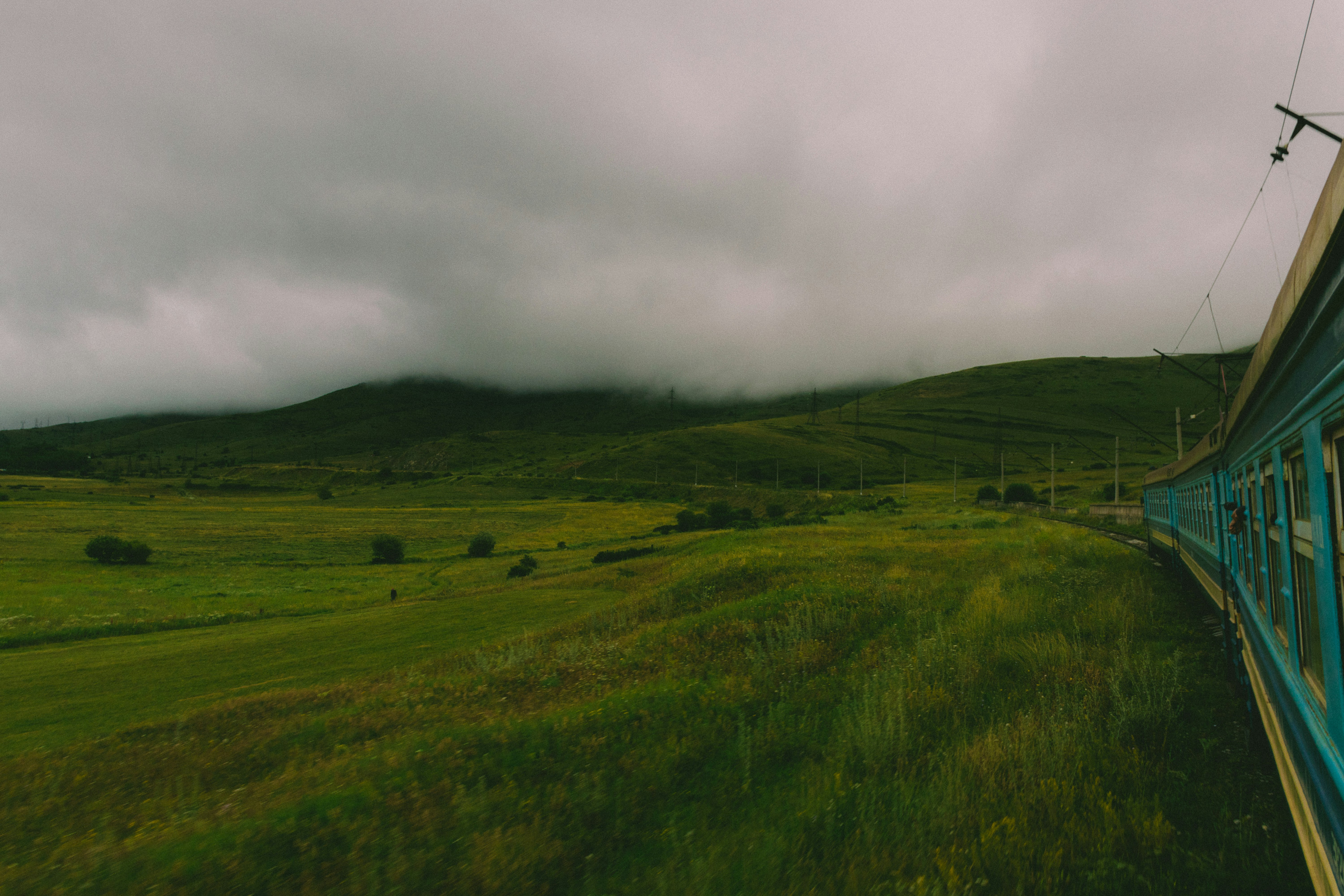 Blue Train Gliding Along a Green Horizon