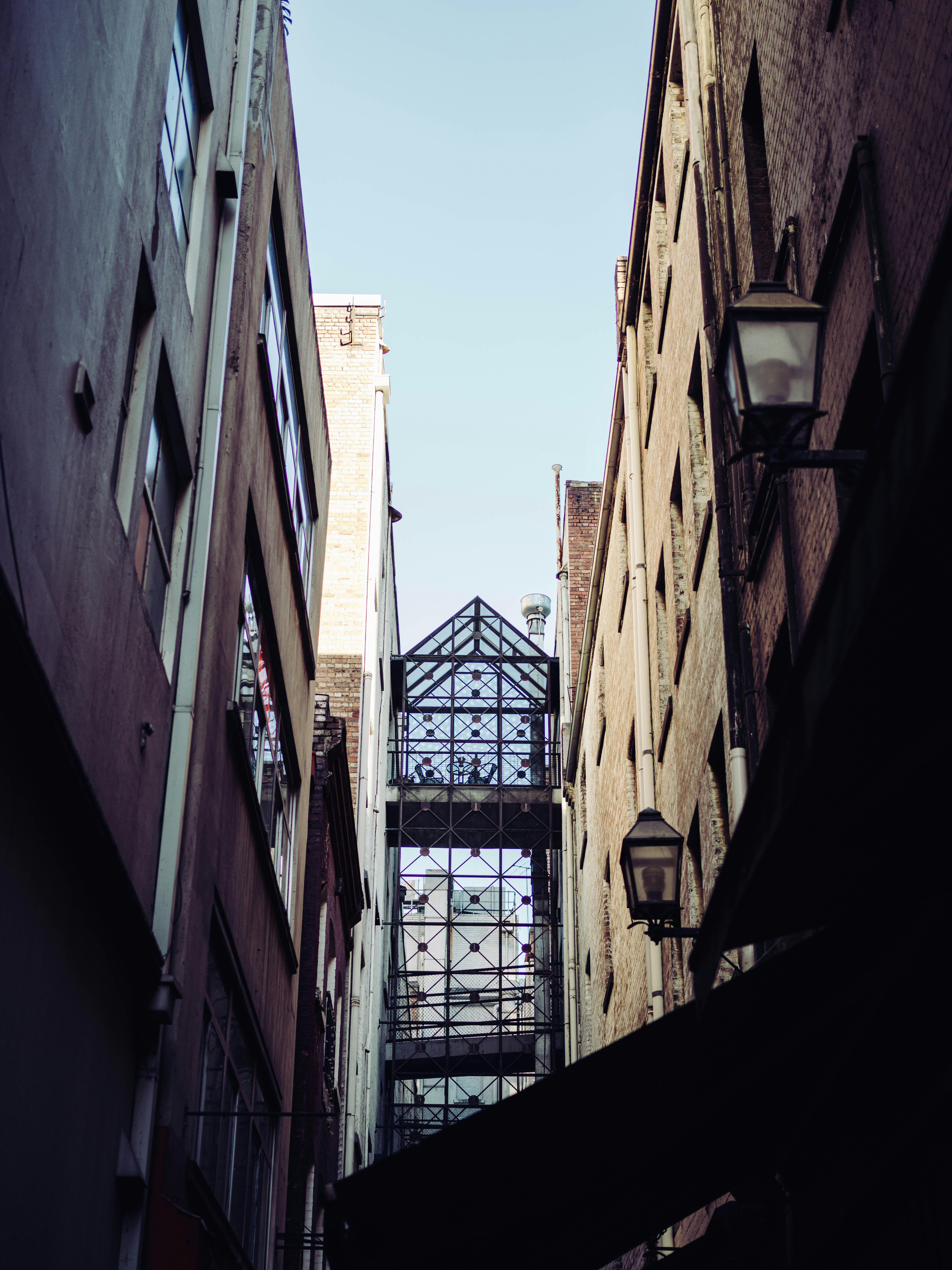 A Narrow Skyward Corridor: Glass Atrium Framed by Brick Facades