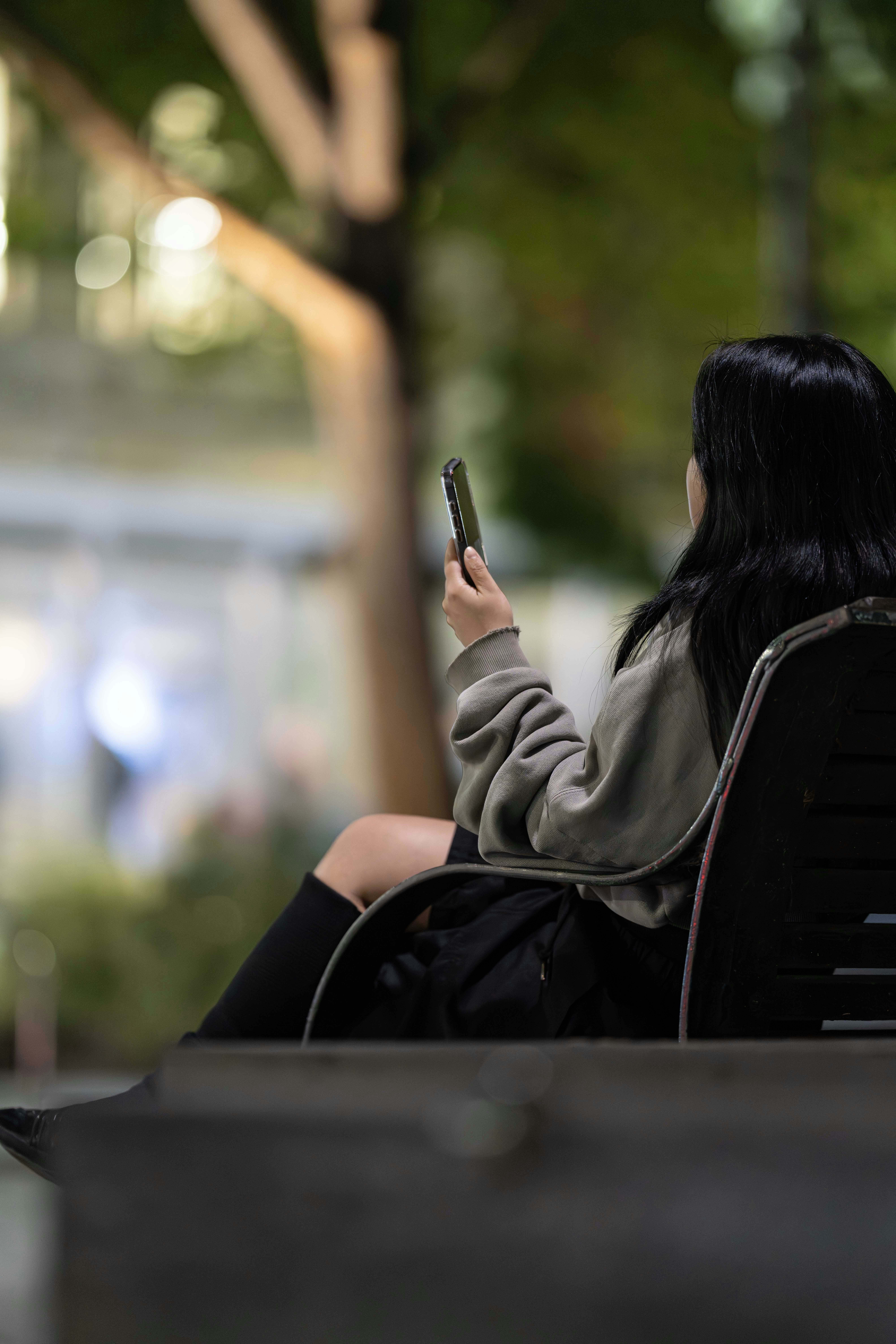 Quiet Portrait on a Park Bench: Phone in Hand, Evening Calm