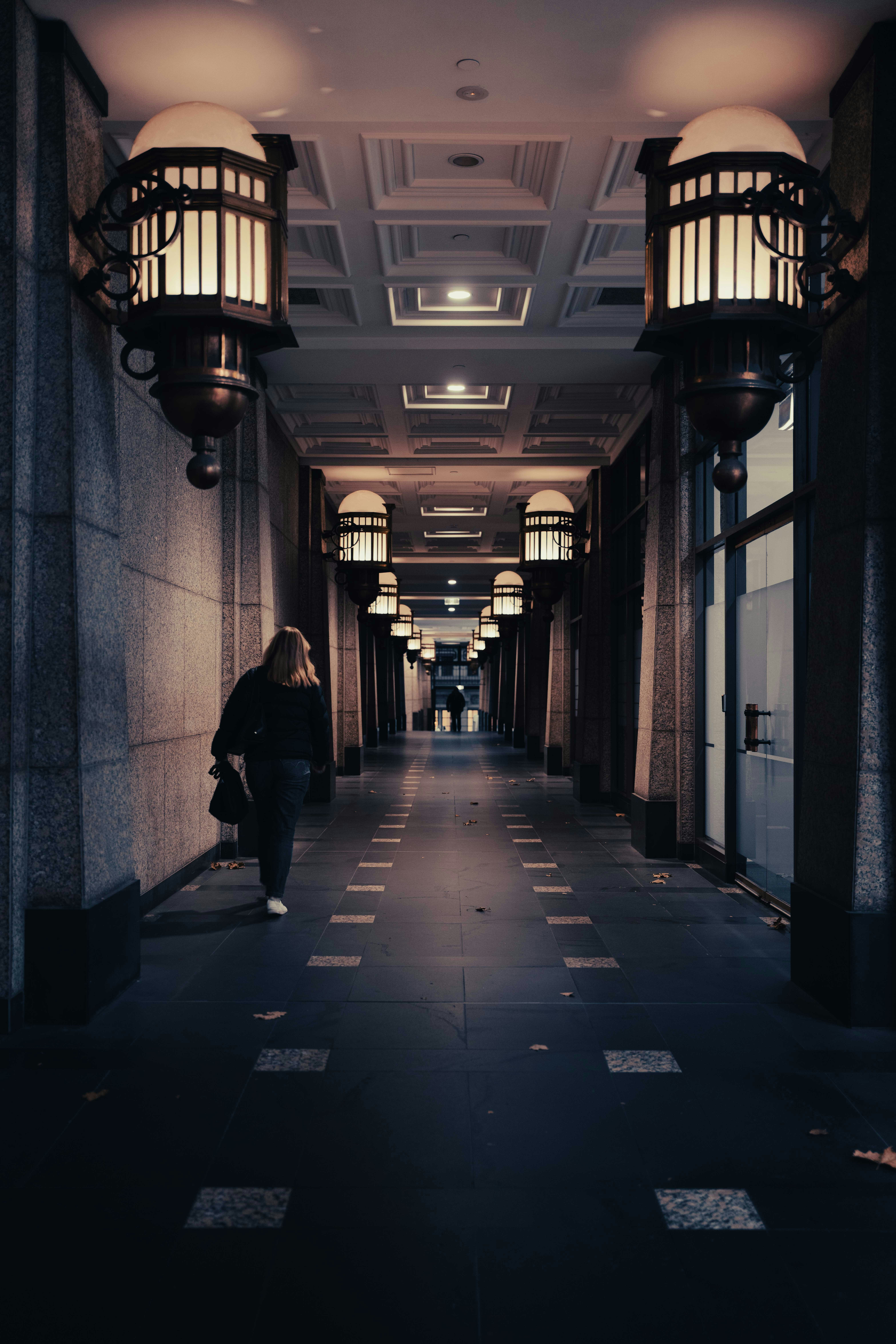 Lantern-lit walkway: a lone traveler in a grand arcade