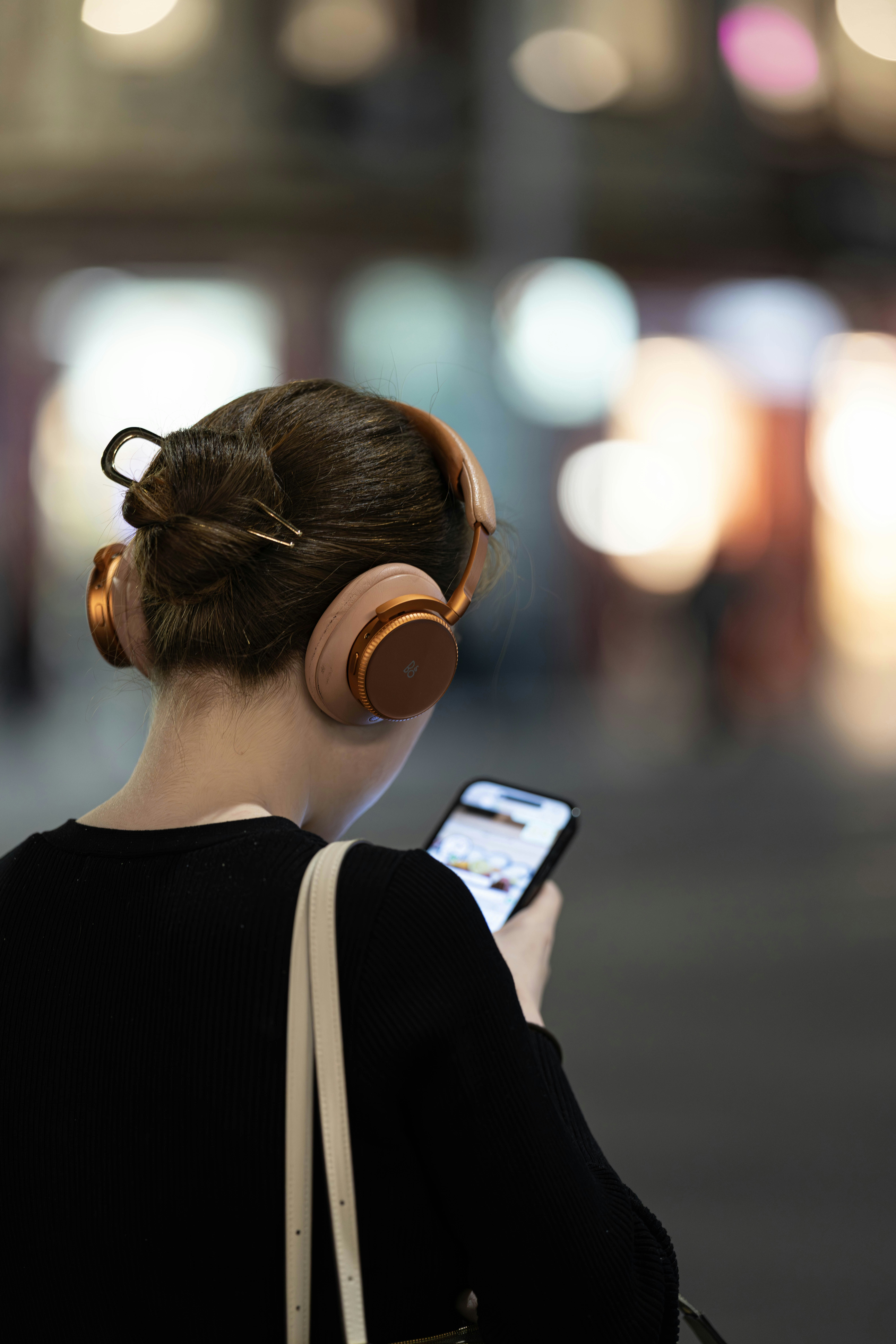 Golden Headphones in Focus: Nighttime Stroll with a Glance at the Screen